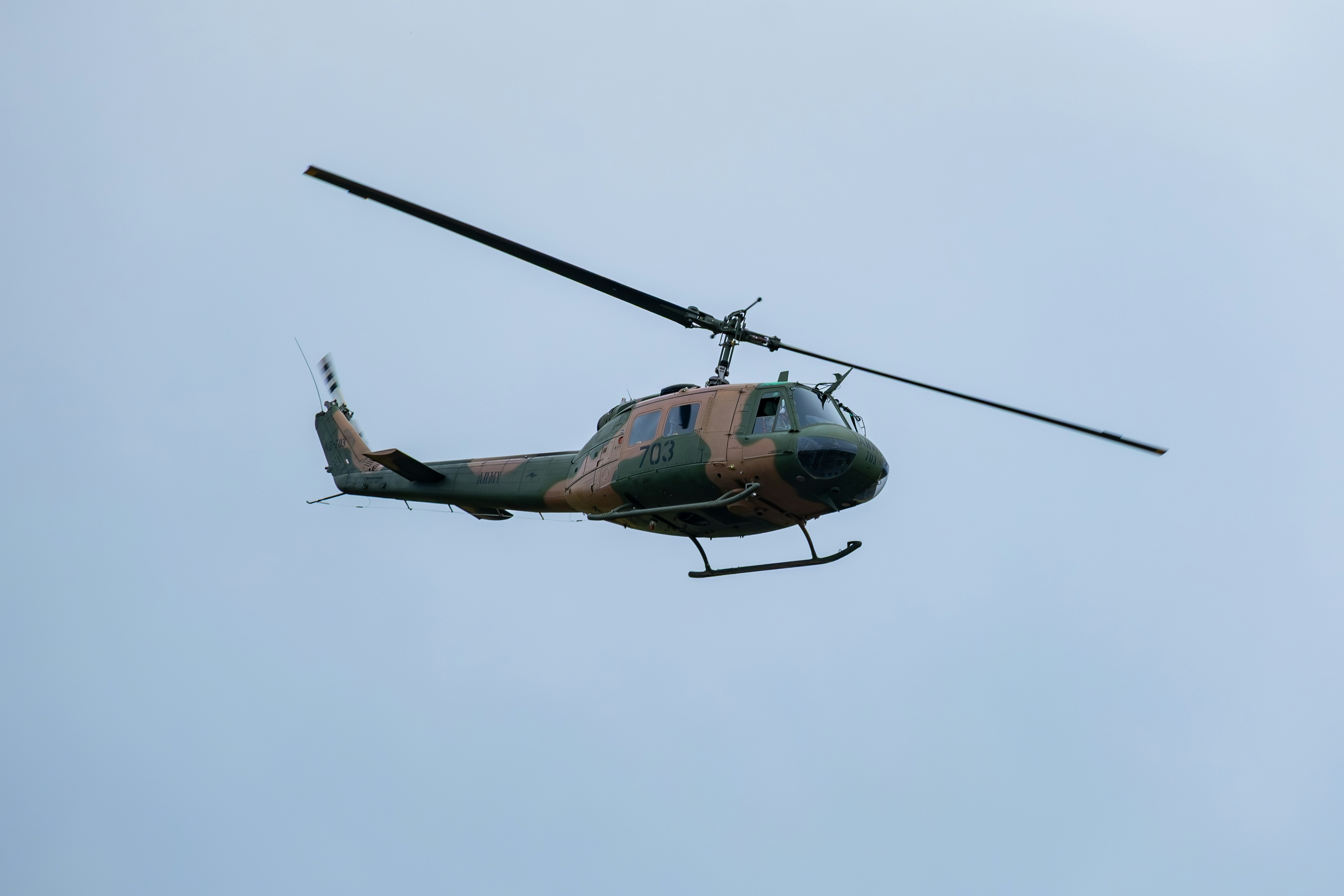 Camouflaged chopper in flight against clear blue sky
