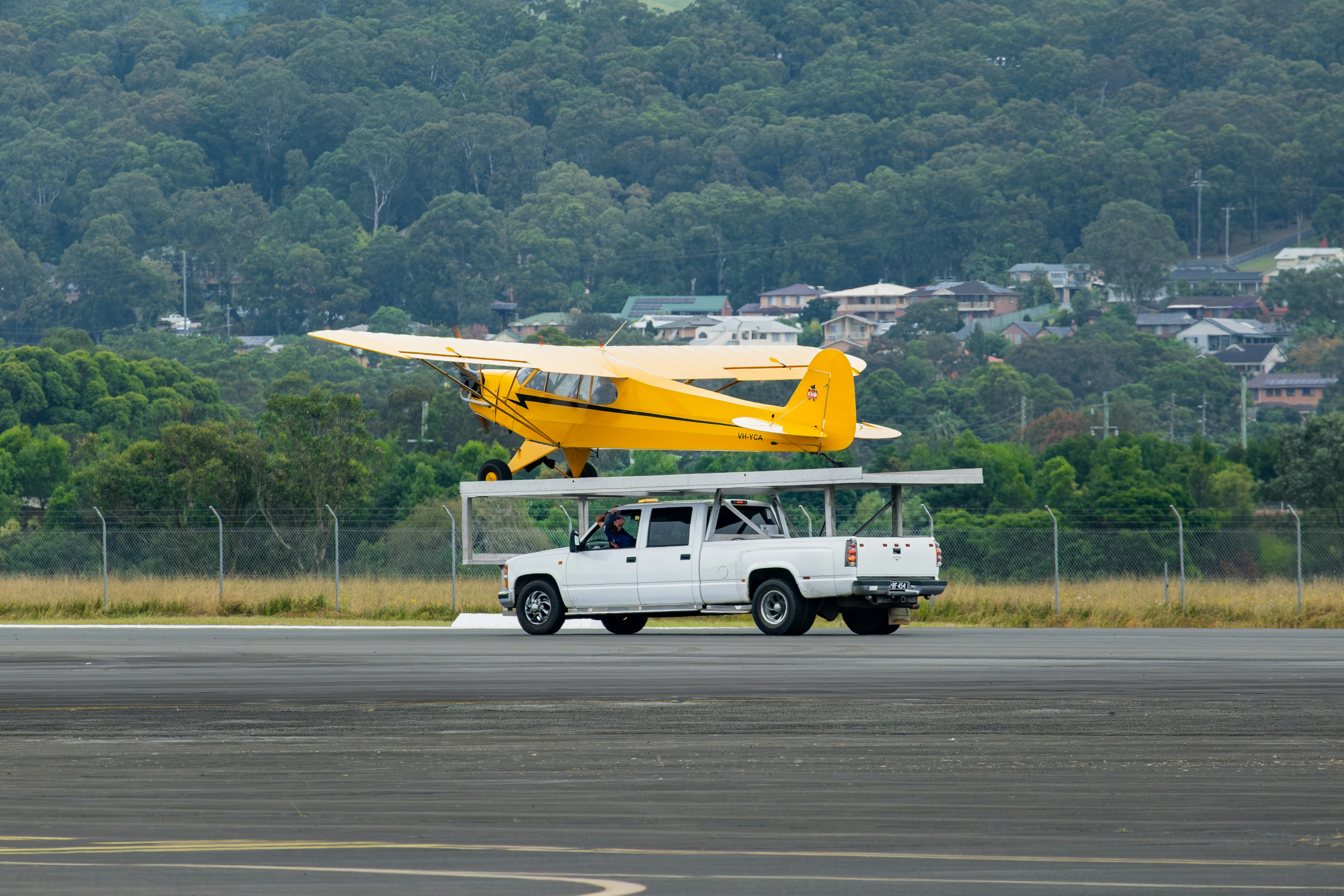 Yellow ultralight on a white pickup in a grassy airfield