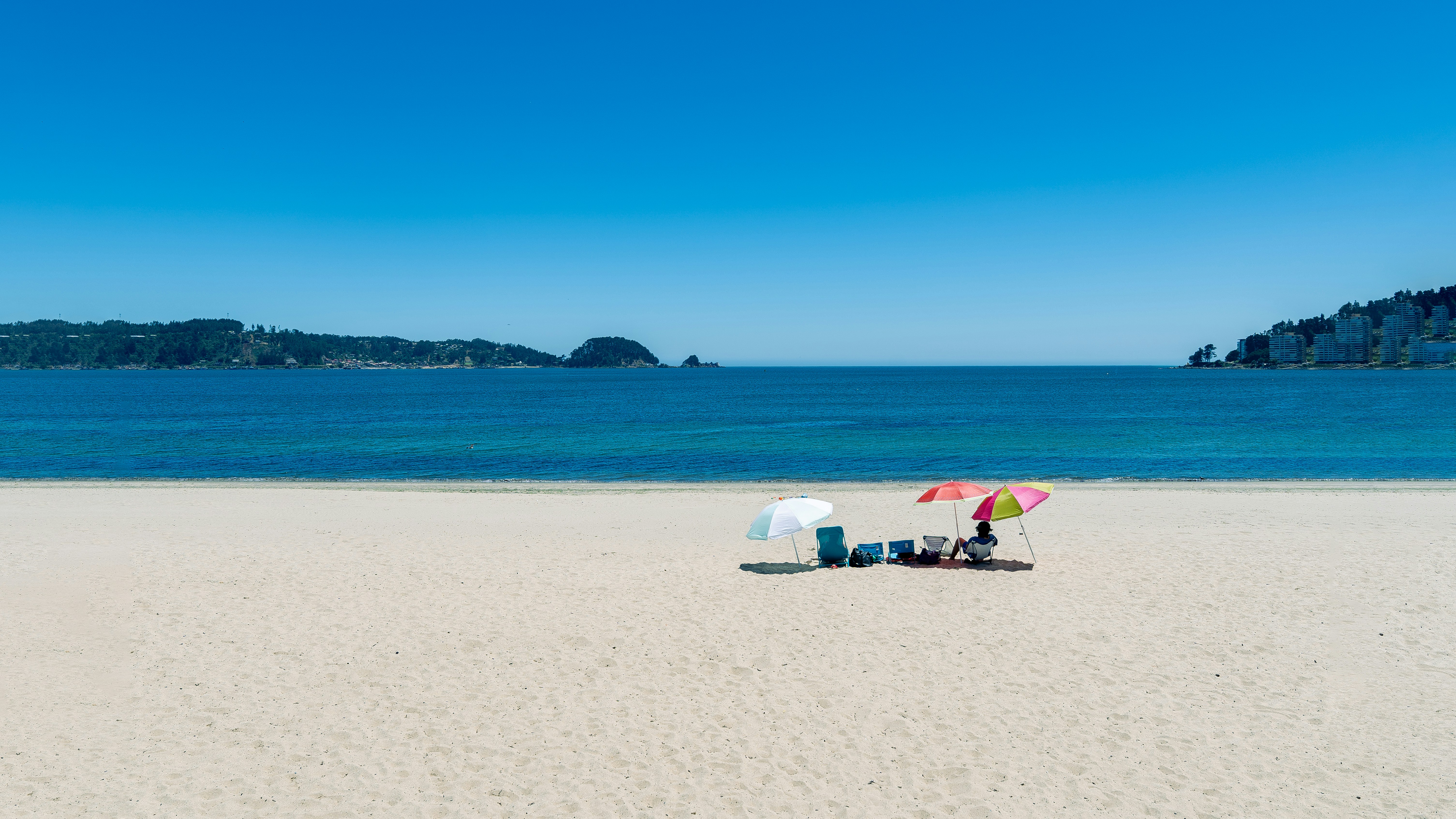 Quiet Strip of Paradise: Two Umbrellas and Sunbathers on a Pristine Beach