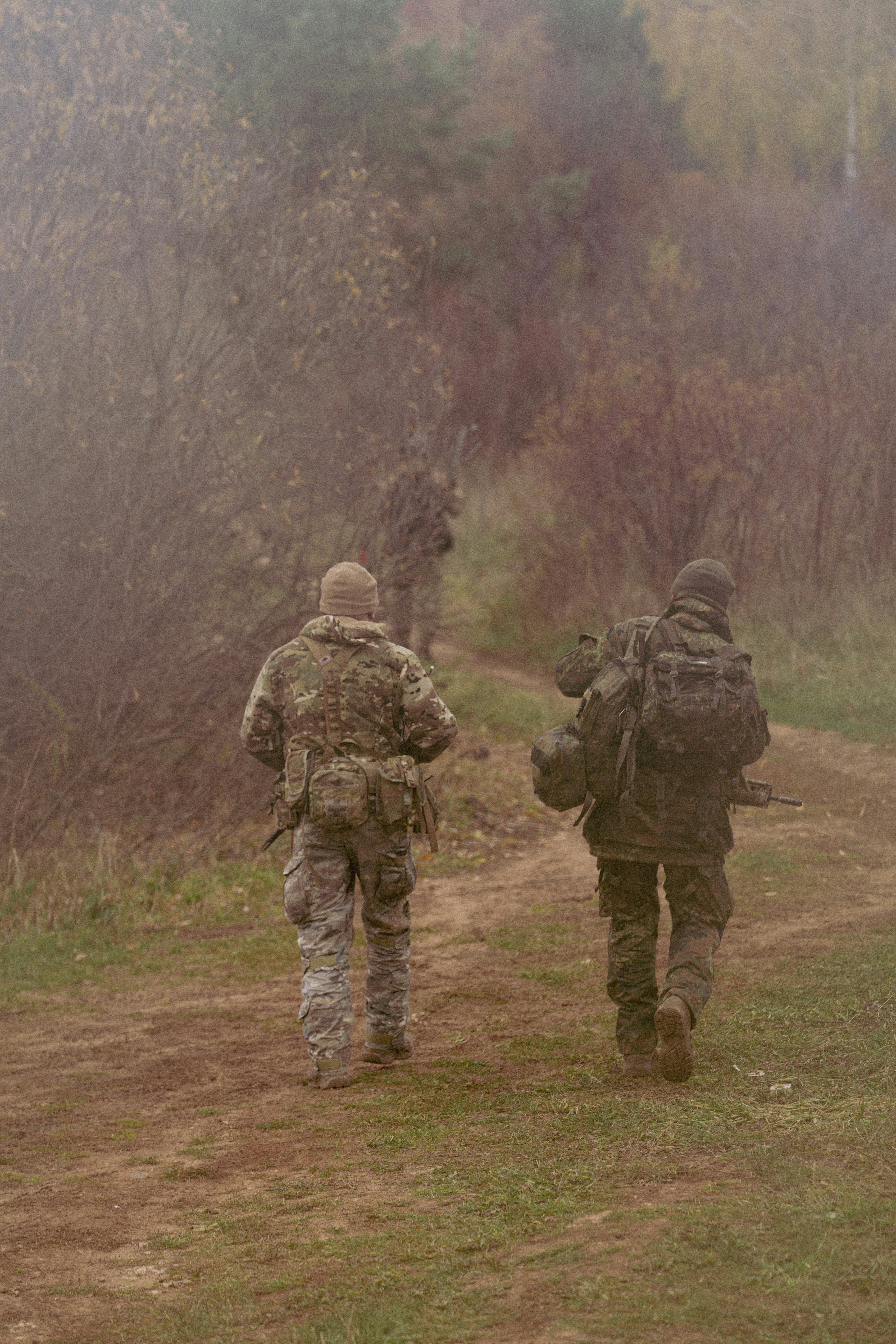 Two soldiers marching along a misty woodland path