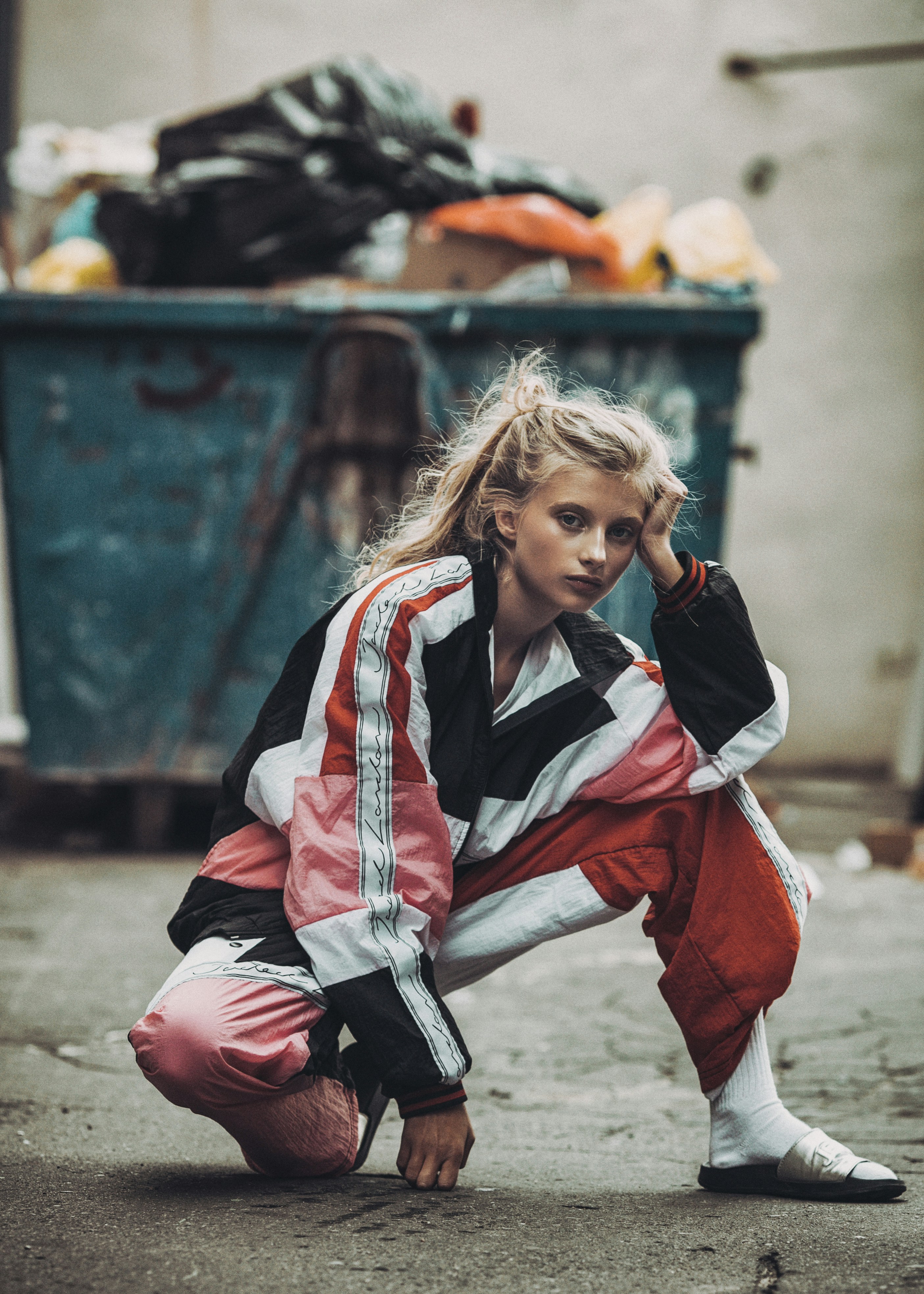 Retro Street Aura: A Bold Runner crouches beside a dumpster in color-blocked windbreaker