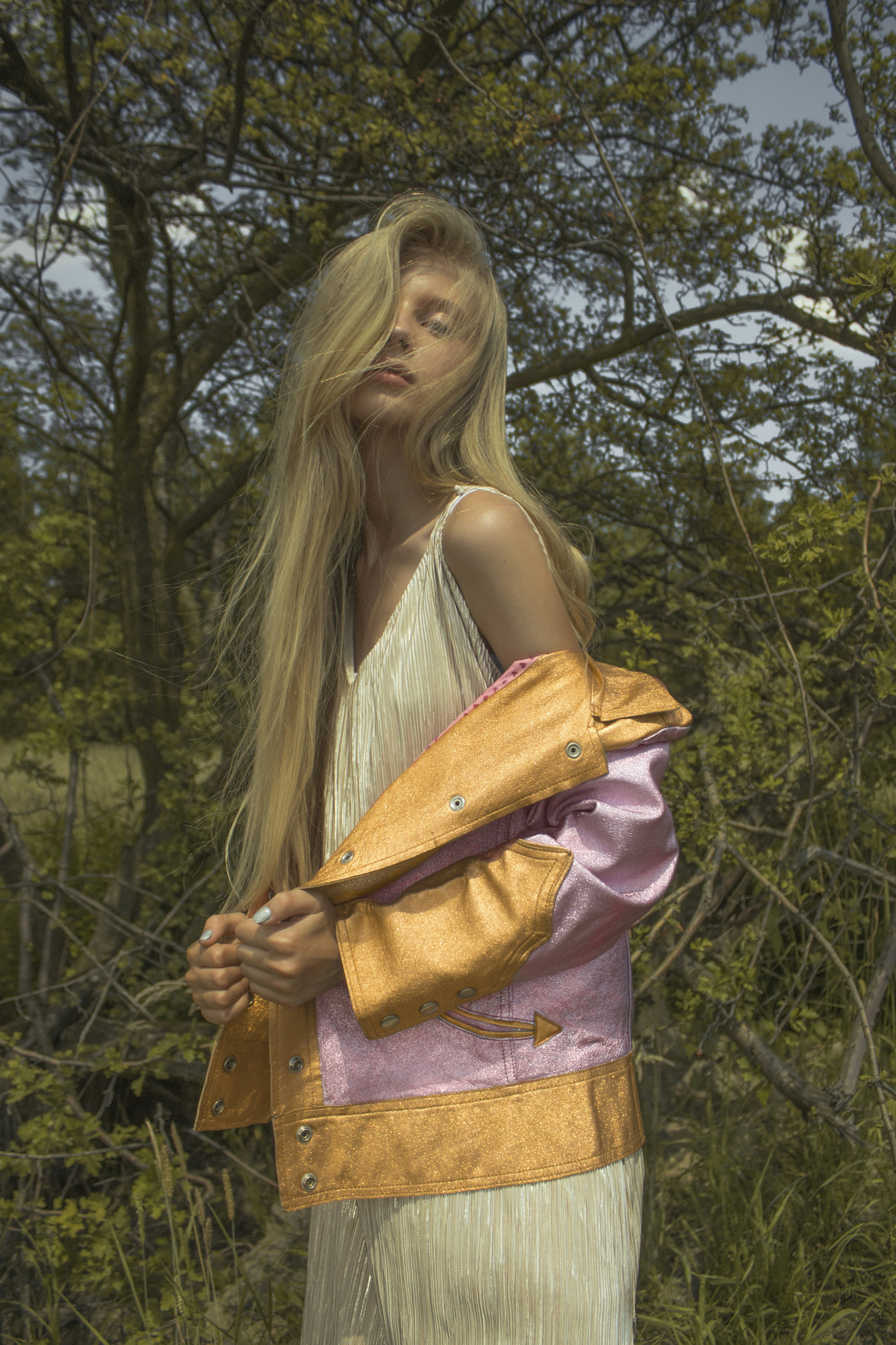 Sunlit Serpent: A Woman in a Metallic Jacket amid Quiet Woodland