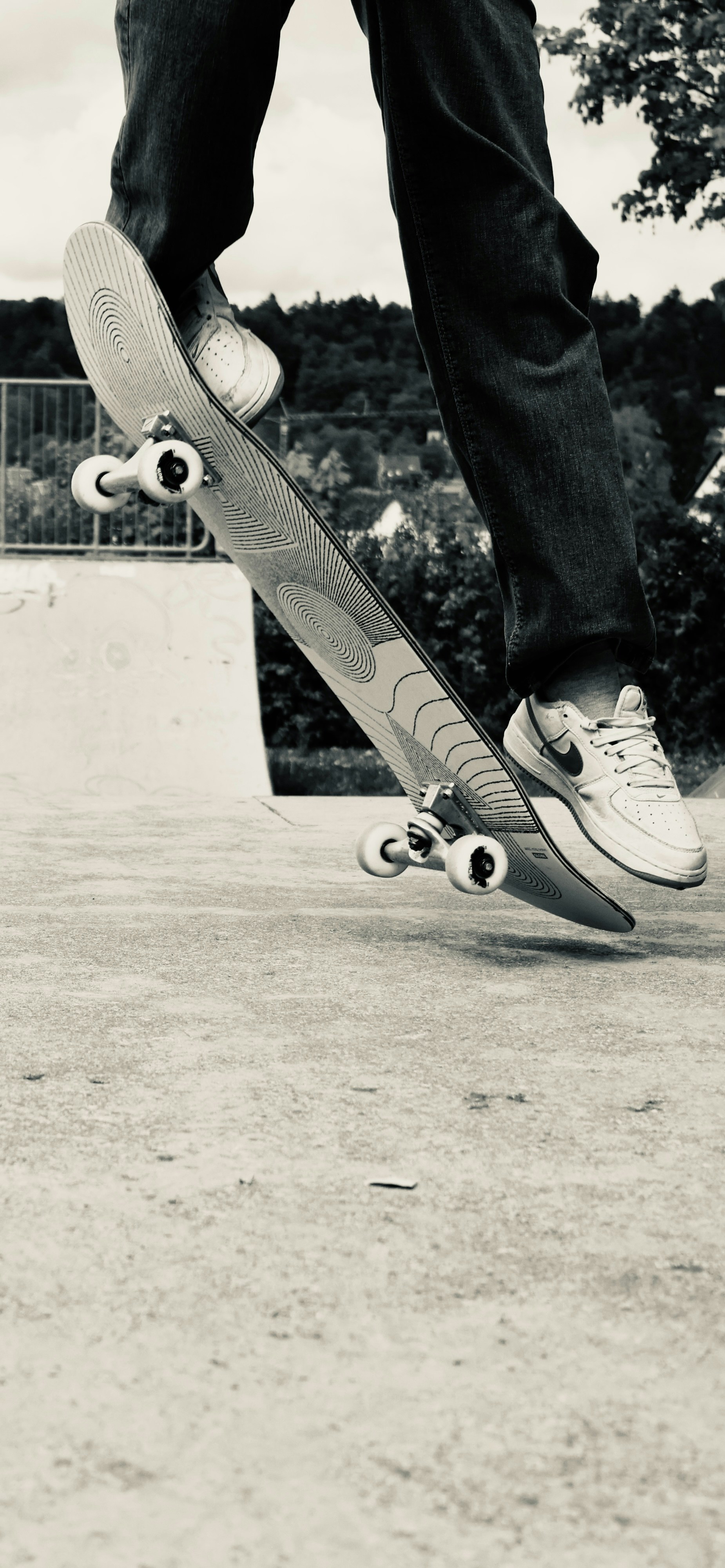 Kickflip in monochrome: a skateboarder mid-air over the concrete park