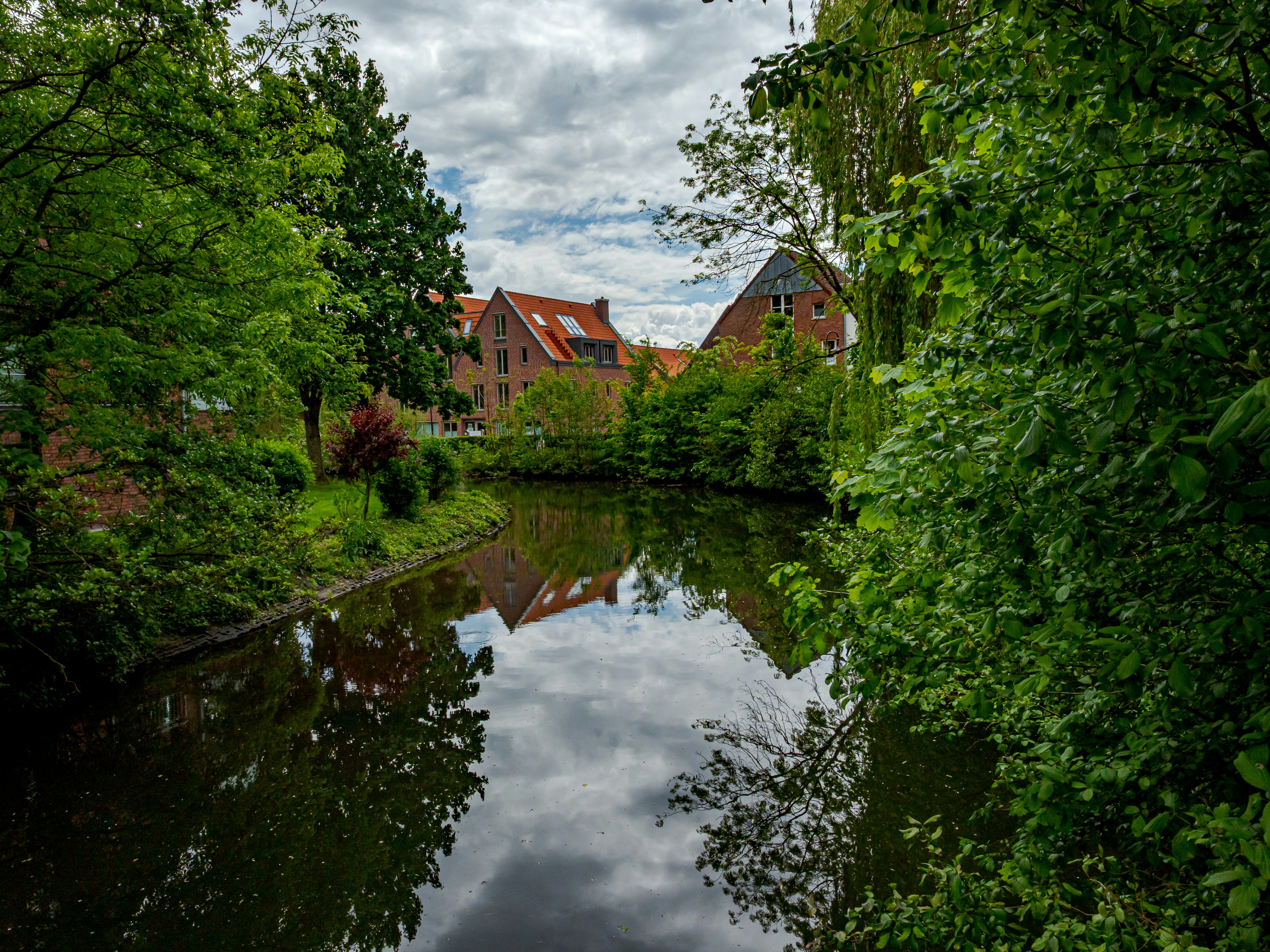 Brick Awned Riverside Village Reflects in Quiet Channel