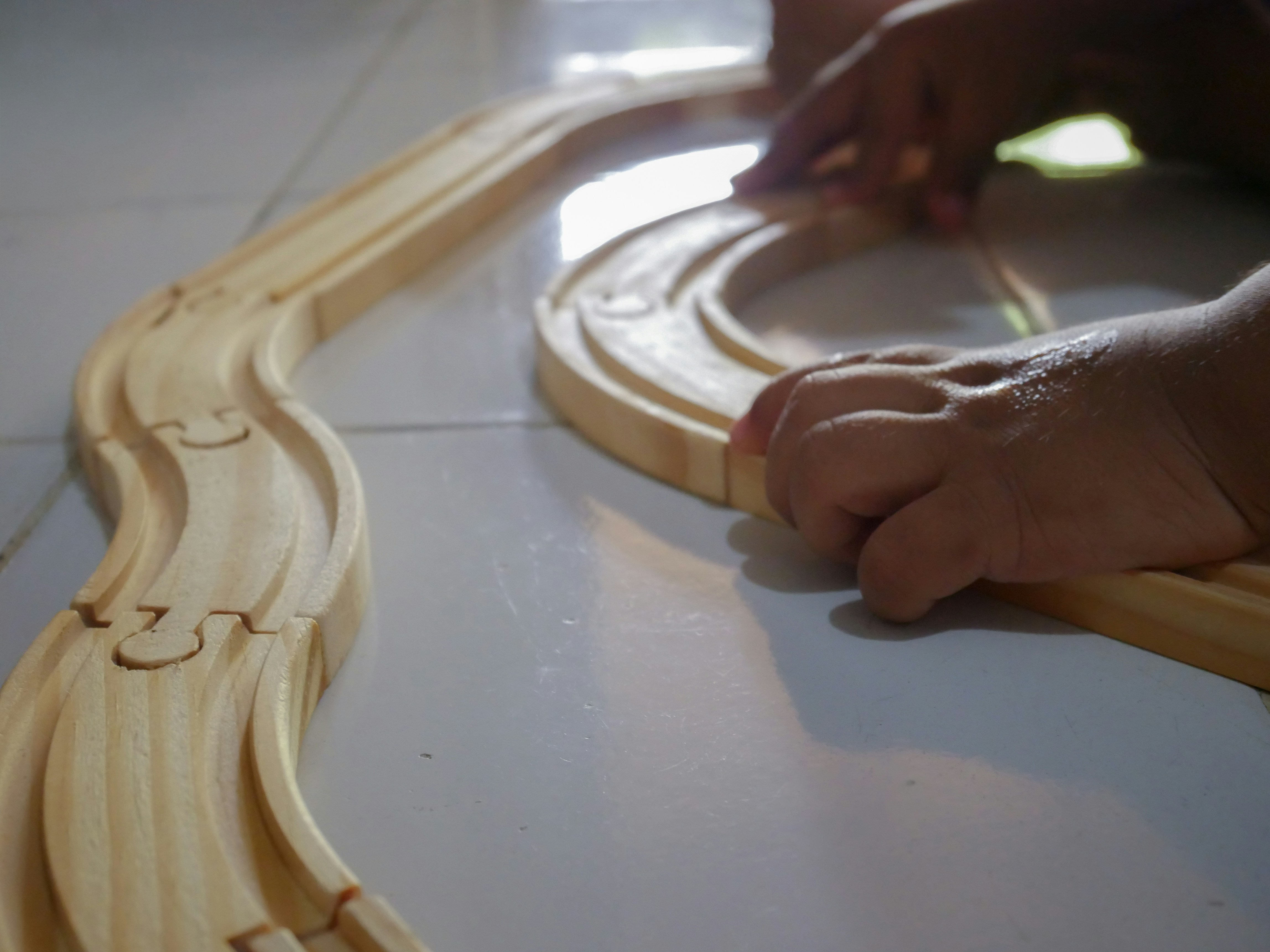 Hands Guiding a Wooden Raceway: Focus on Craft and Play