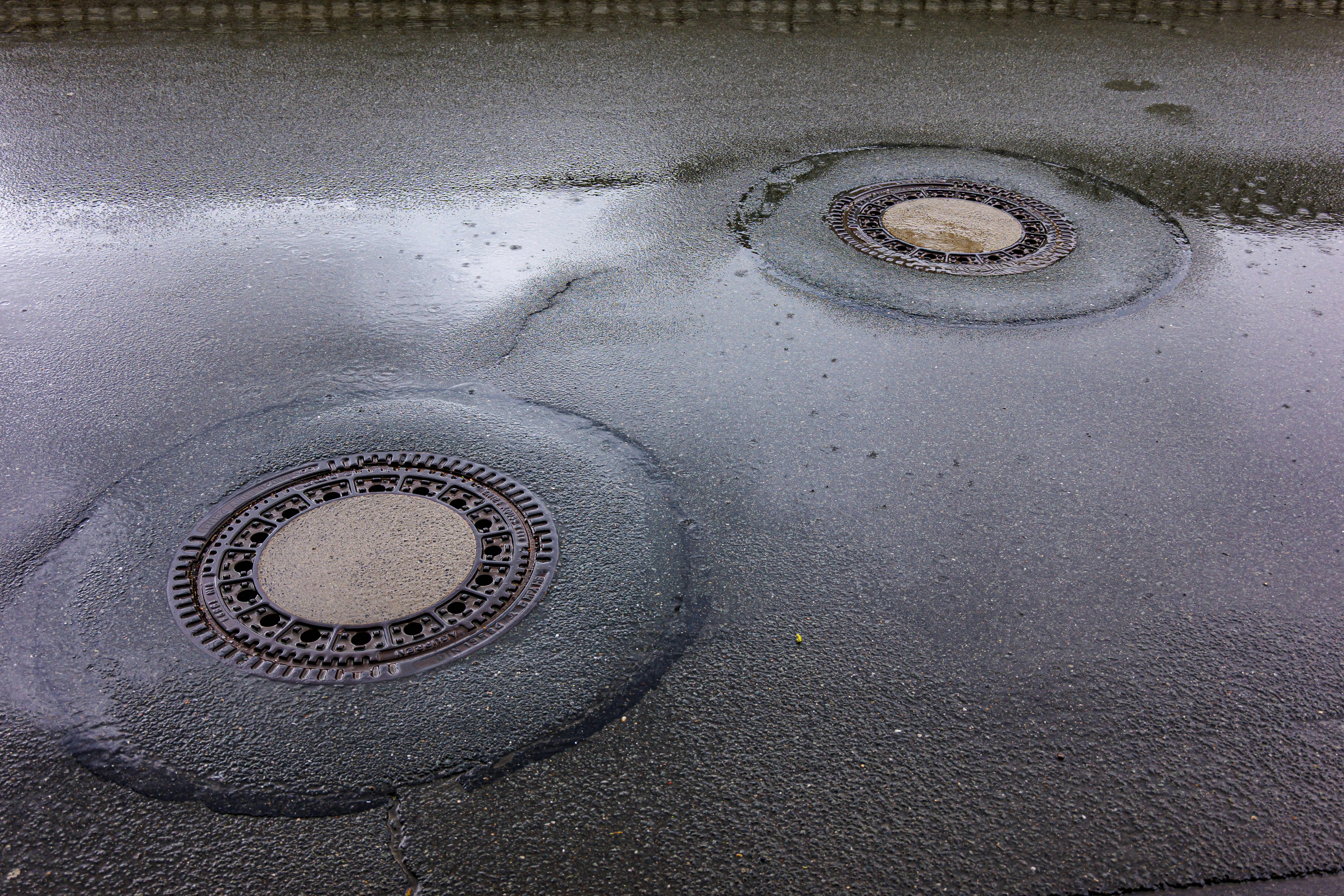 Circular Rain-Washed Drain Flags the Street’s Quiet Afterglow