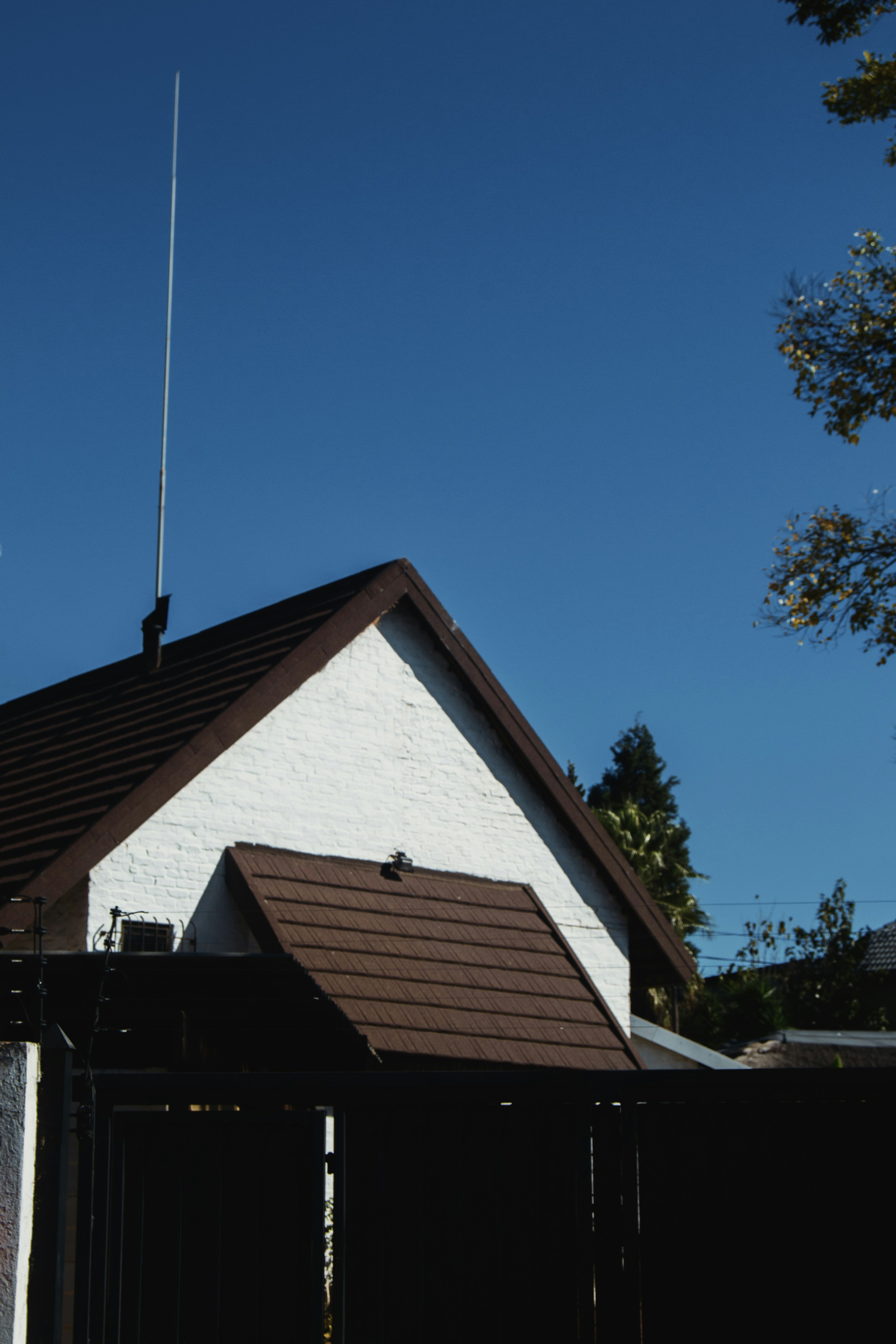 Blue Sky Over a White Cottage with a Hidden Gate