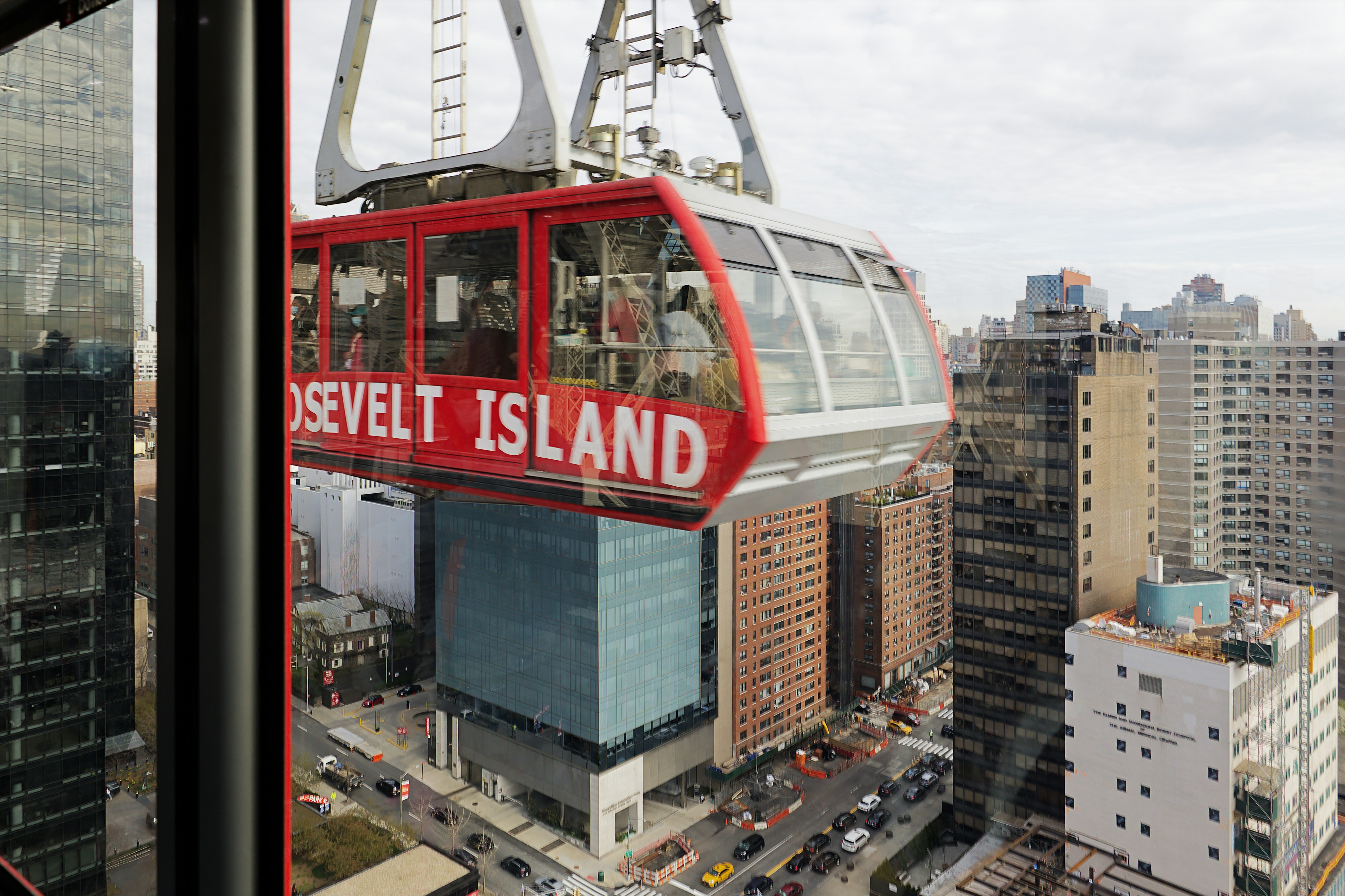 Ropeway Over Manhattan: A Red Gondola Among Glass and Brick