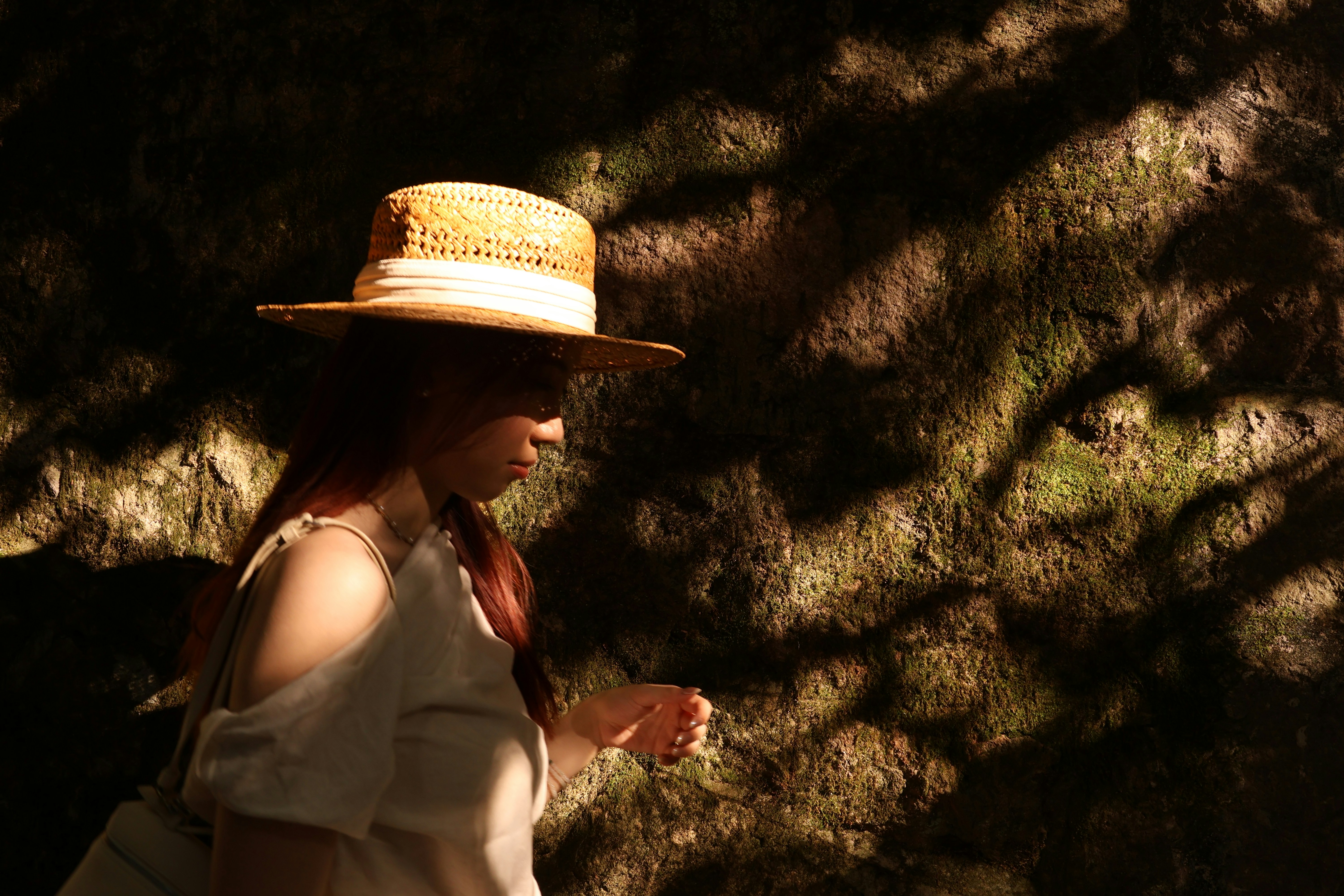 Sunlit Quiet: A Woman in a Straw Hat Under Dappled Shadows