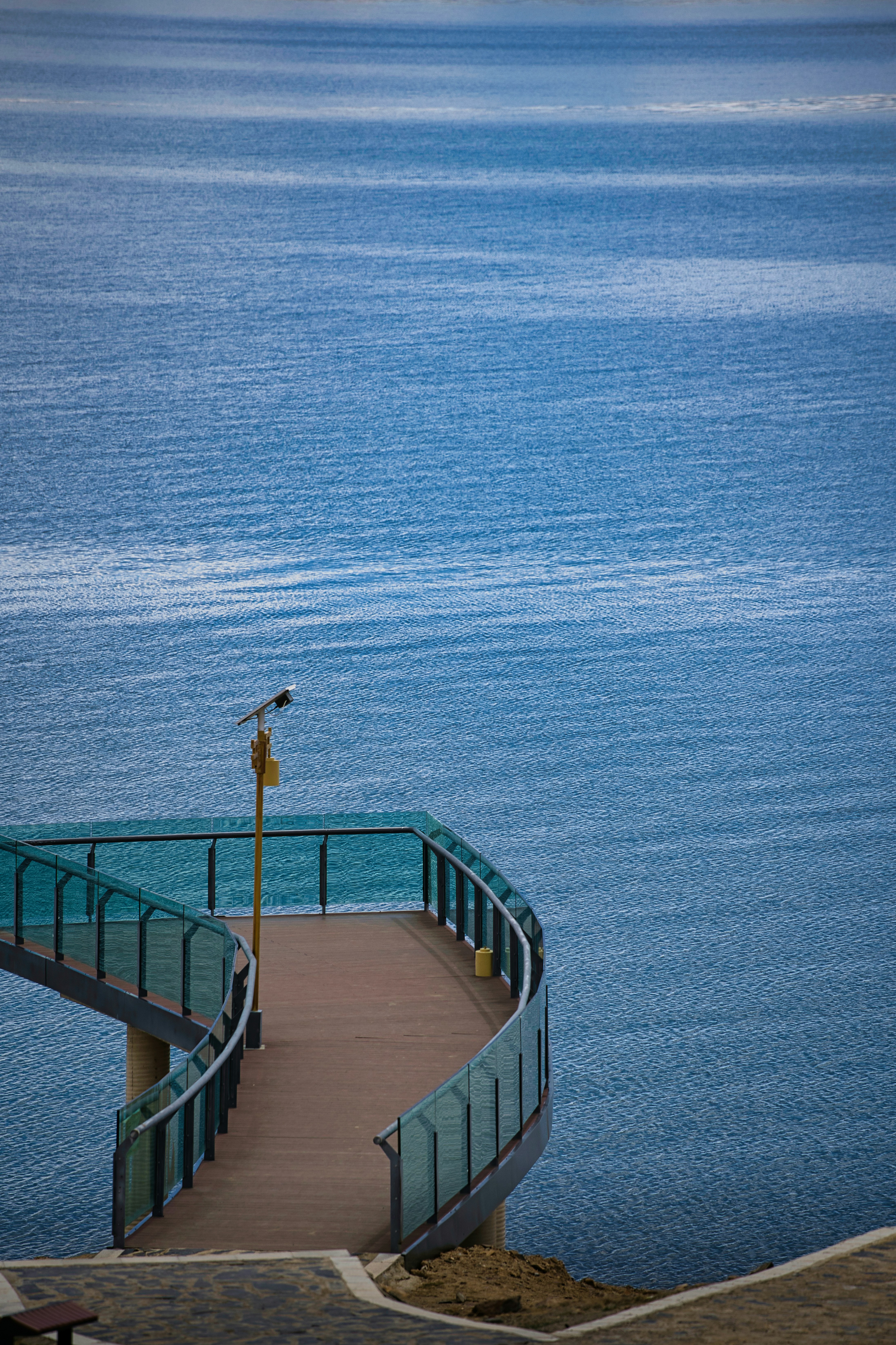 Curved Waterfront Walkway Extends Over Quiet Blue Calm