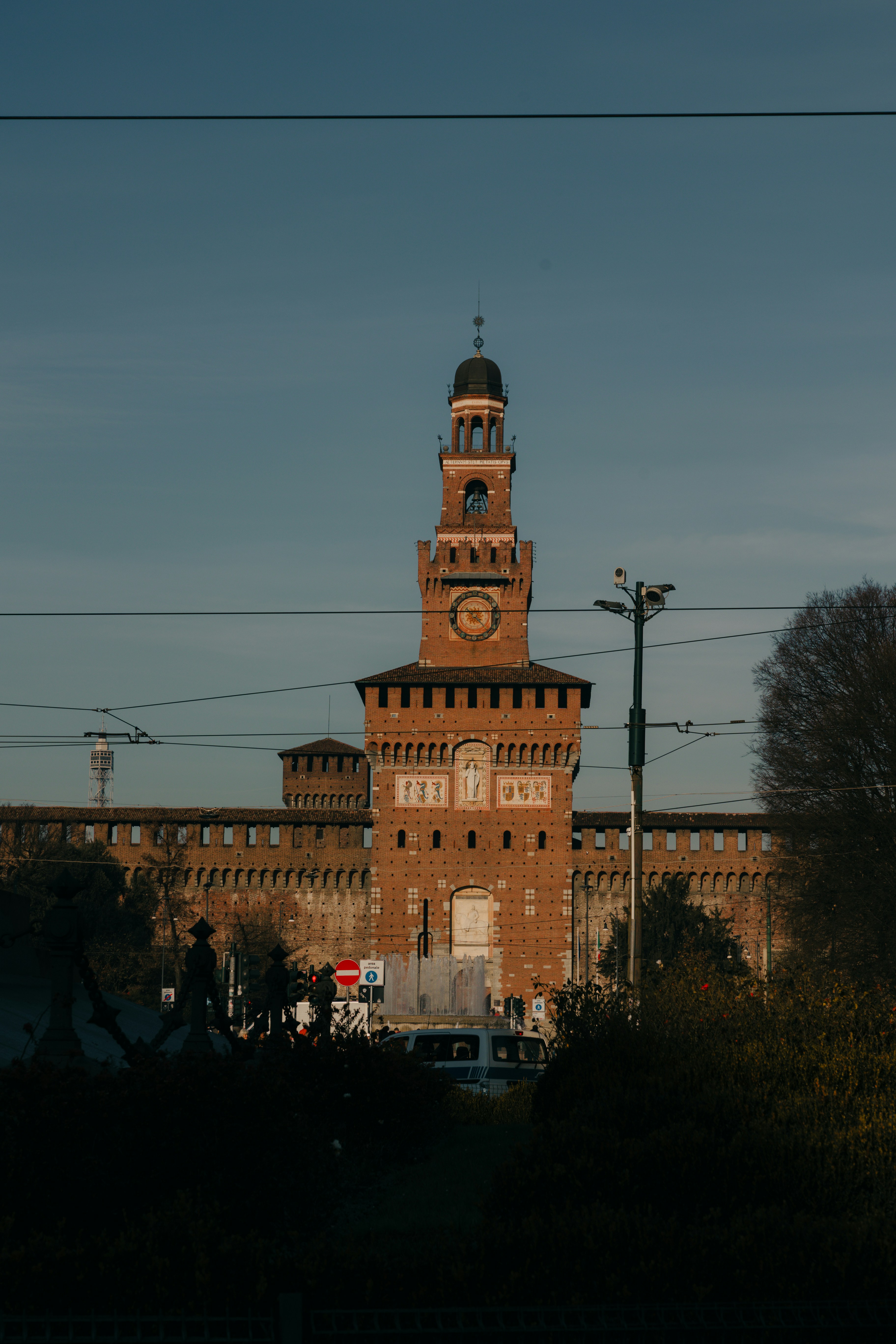 Brick Fortress Gate Rising Above Trams and Shadows