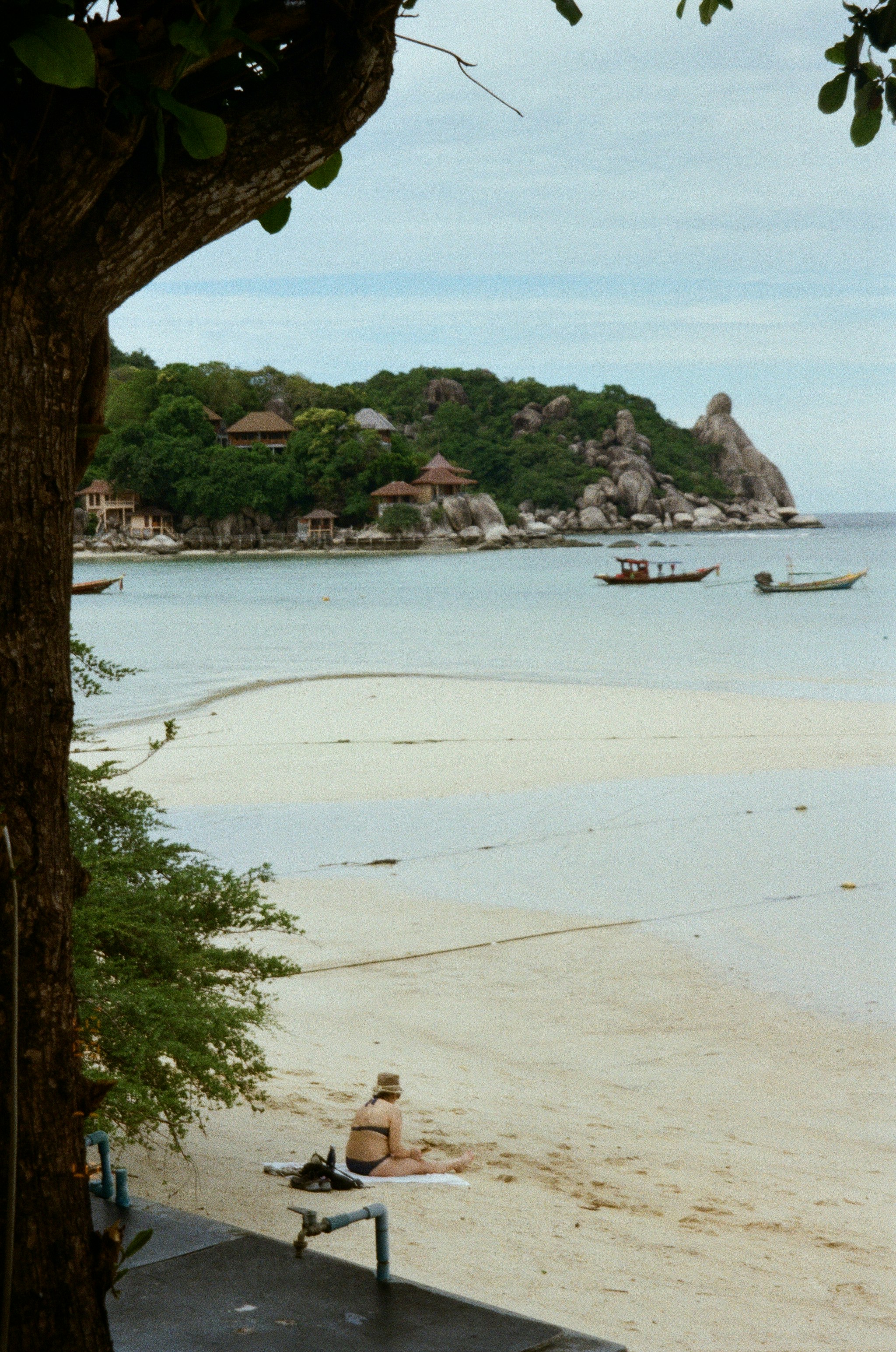 Woman sunbathing on a tropical beach with boats and island. photo ...