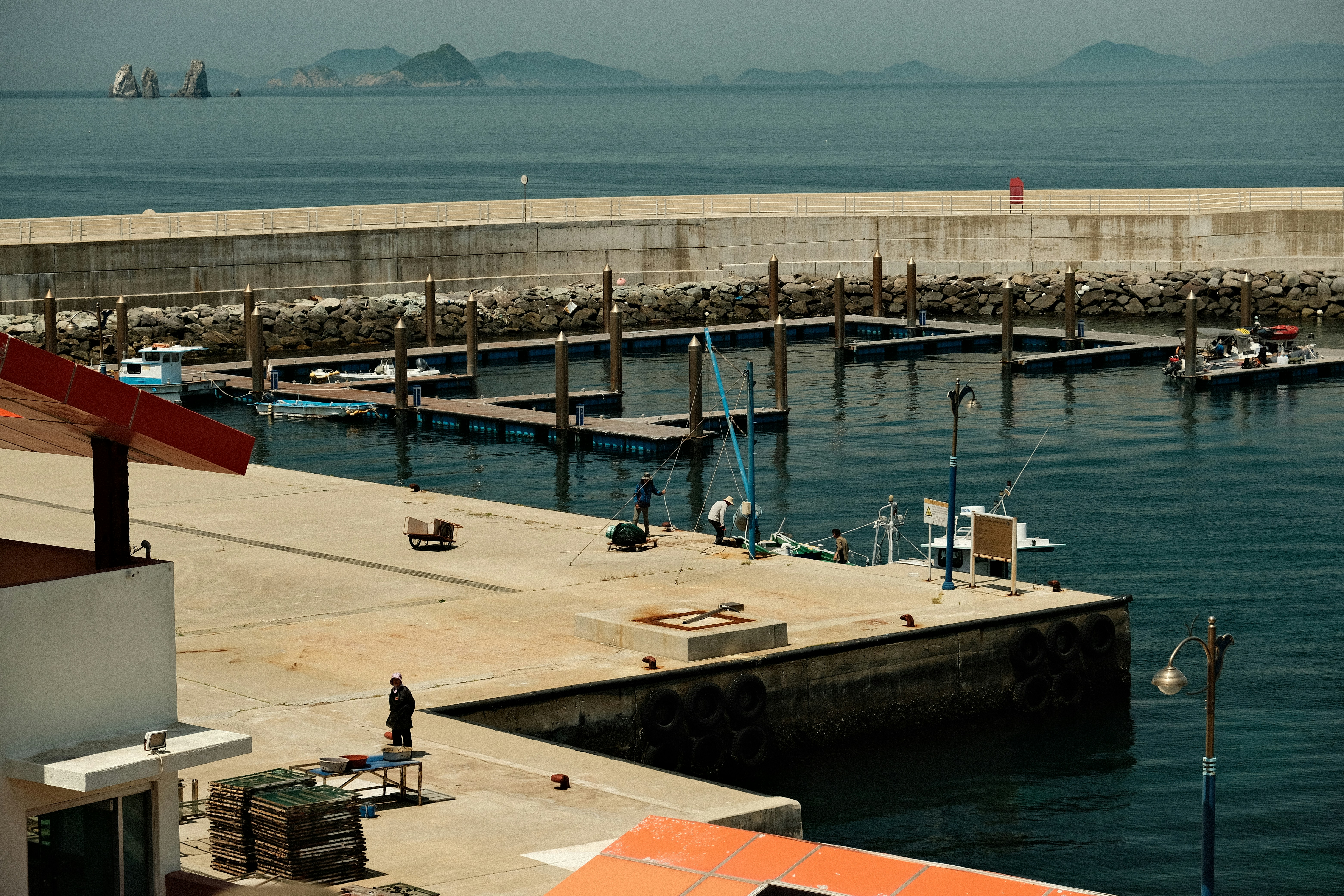Harbor Quiet: Boats, Concrete Pier, and Distant Sea Terraces