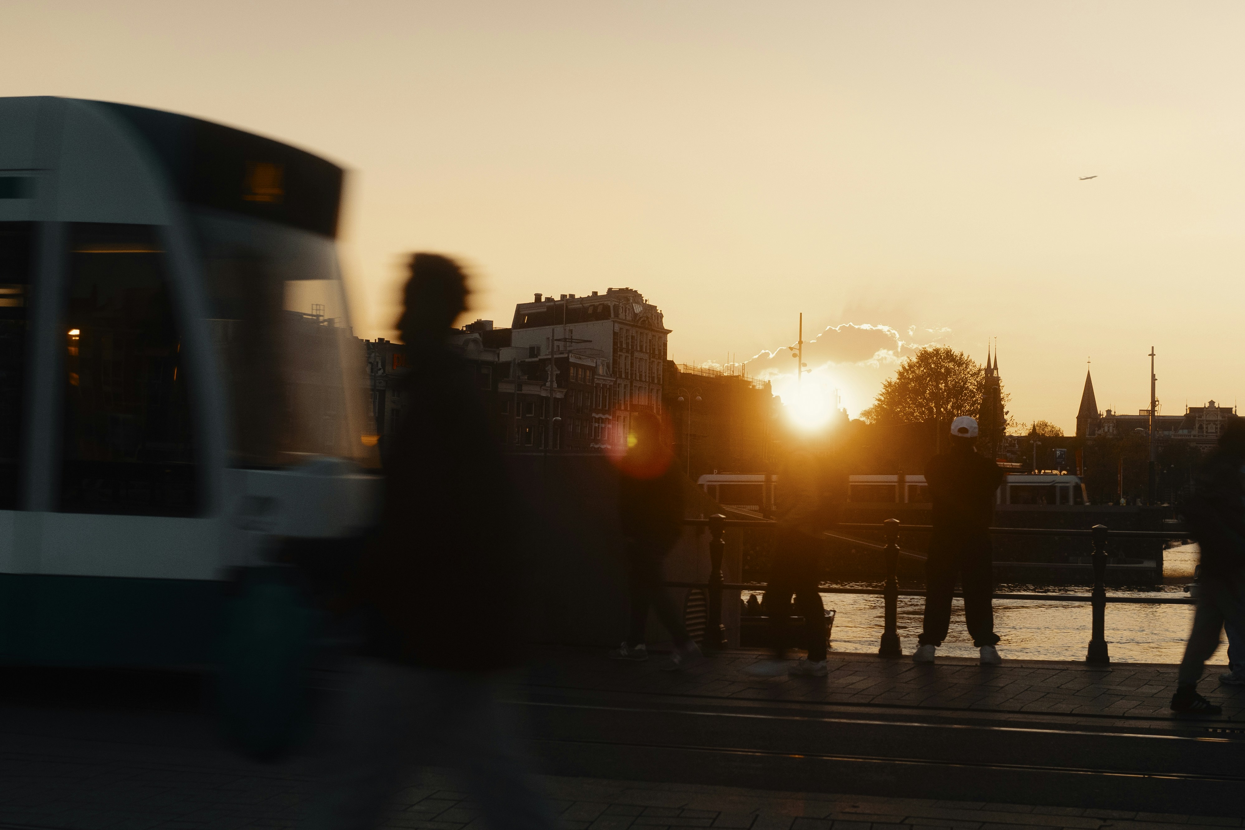 Sunlit silhouettes by the quay: evening transit at the riverfront
