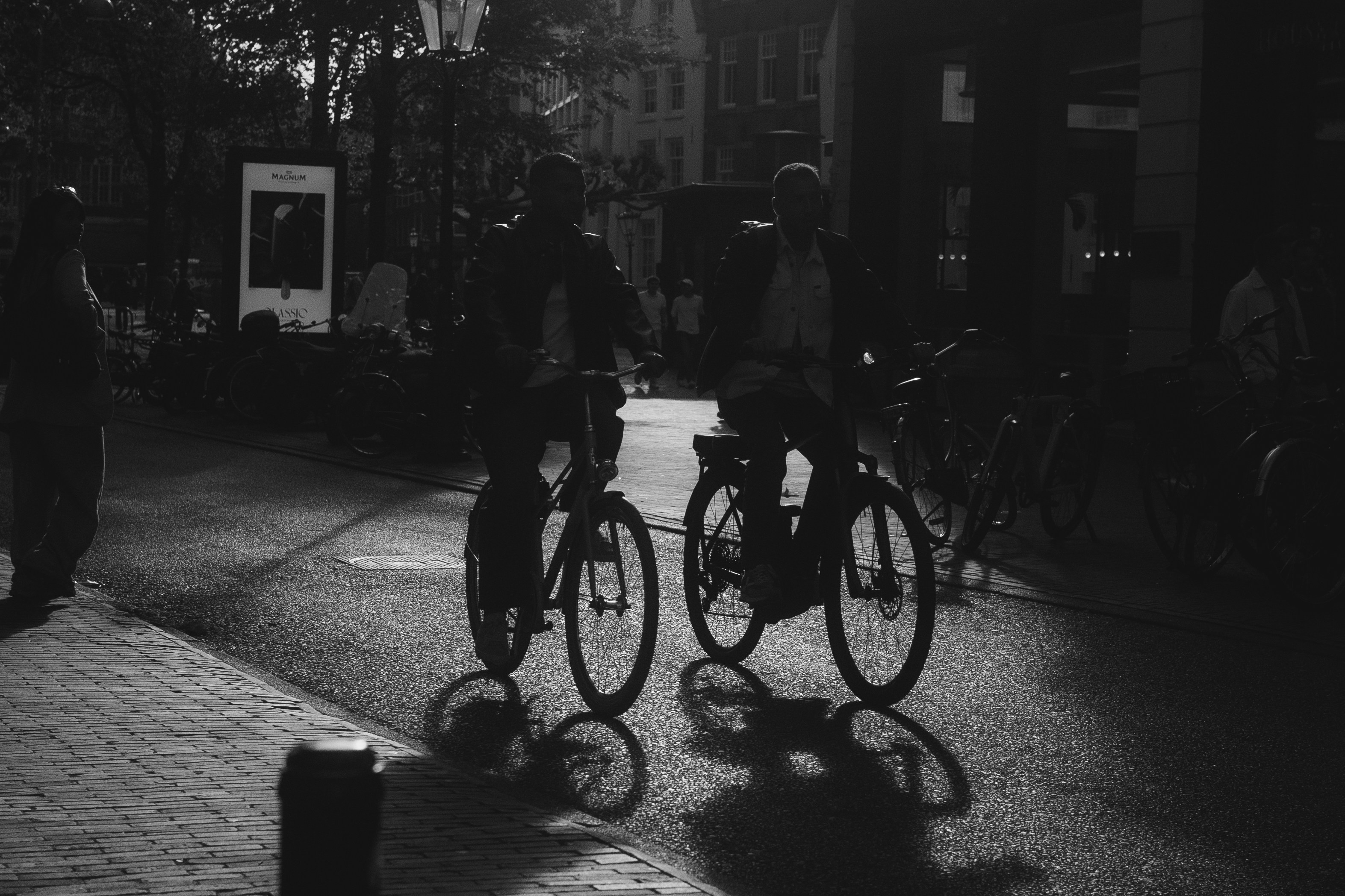 Shadowed cyclists in a sunlit city square