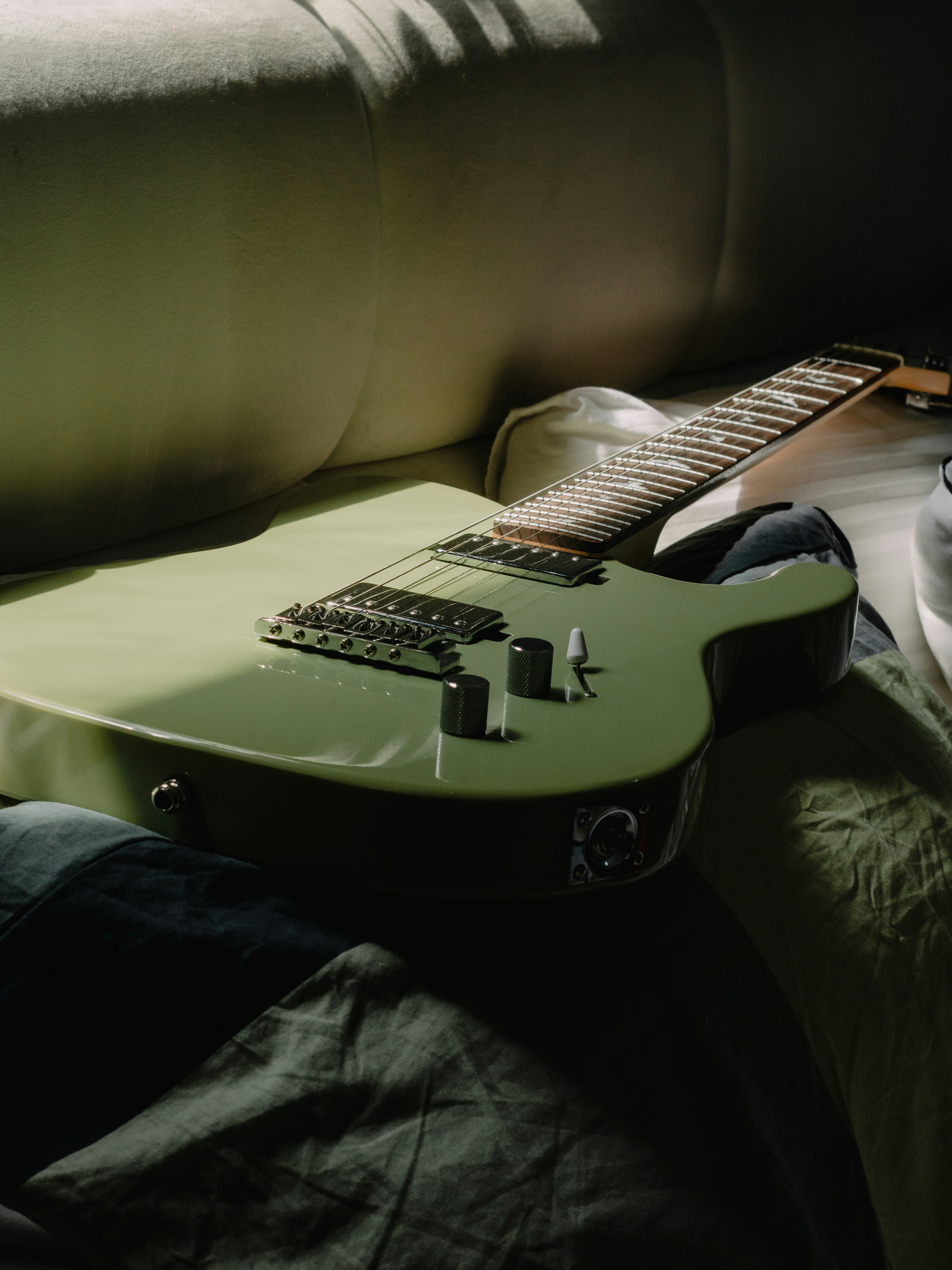Emerald guitar resting on a sunlit quilt