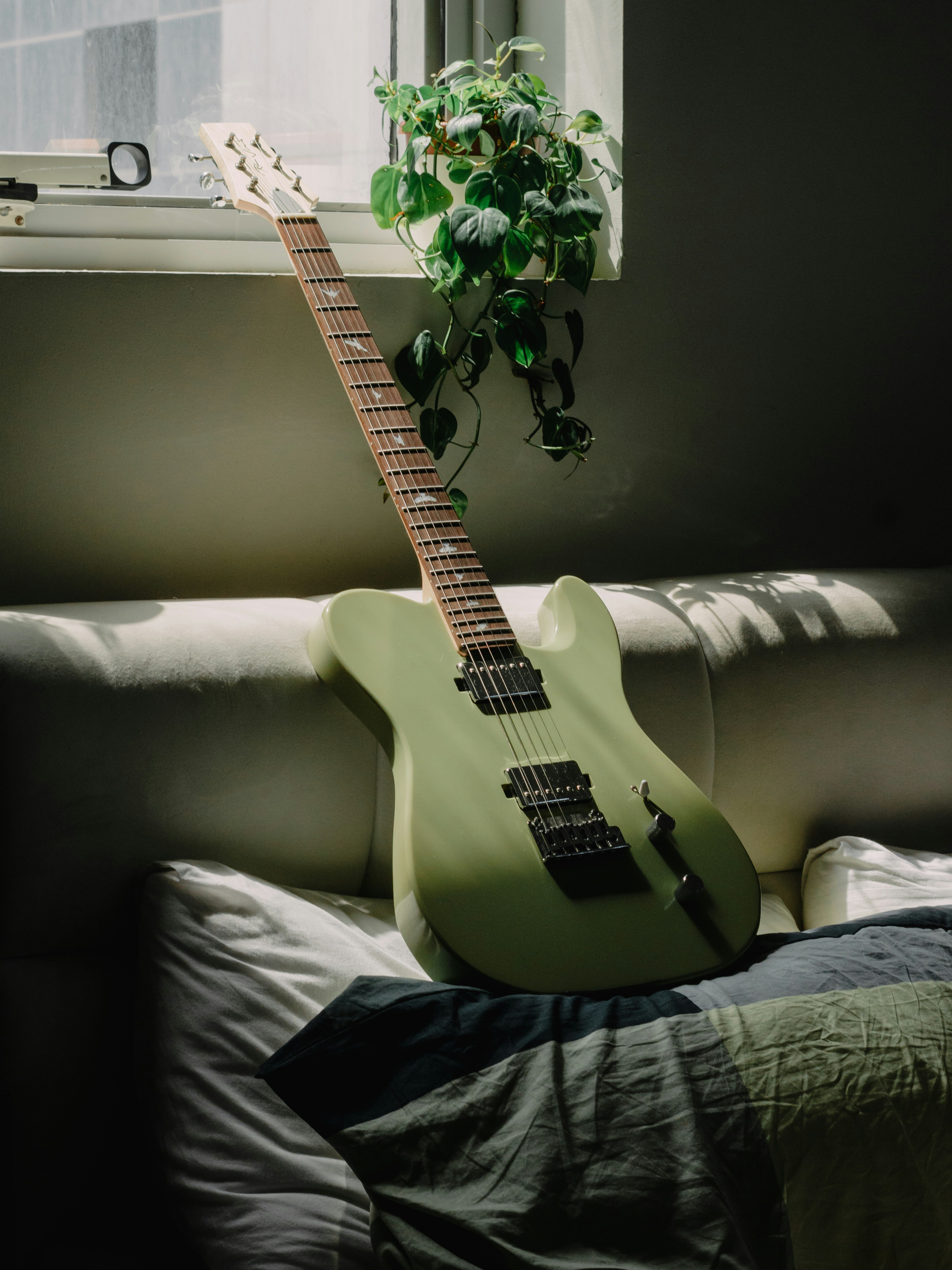 Emerald Rhythm: A Green Electric Guitar Resting by a Sunlit Window