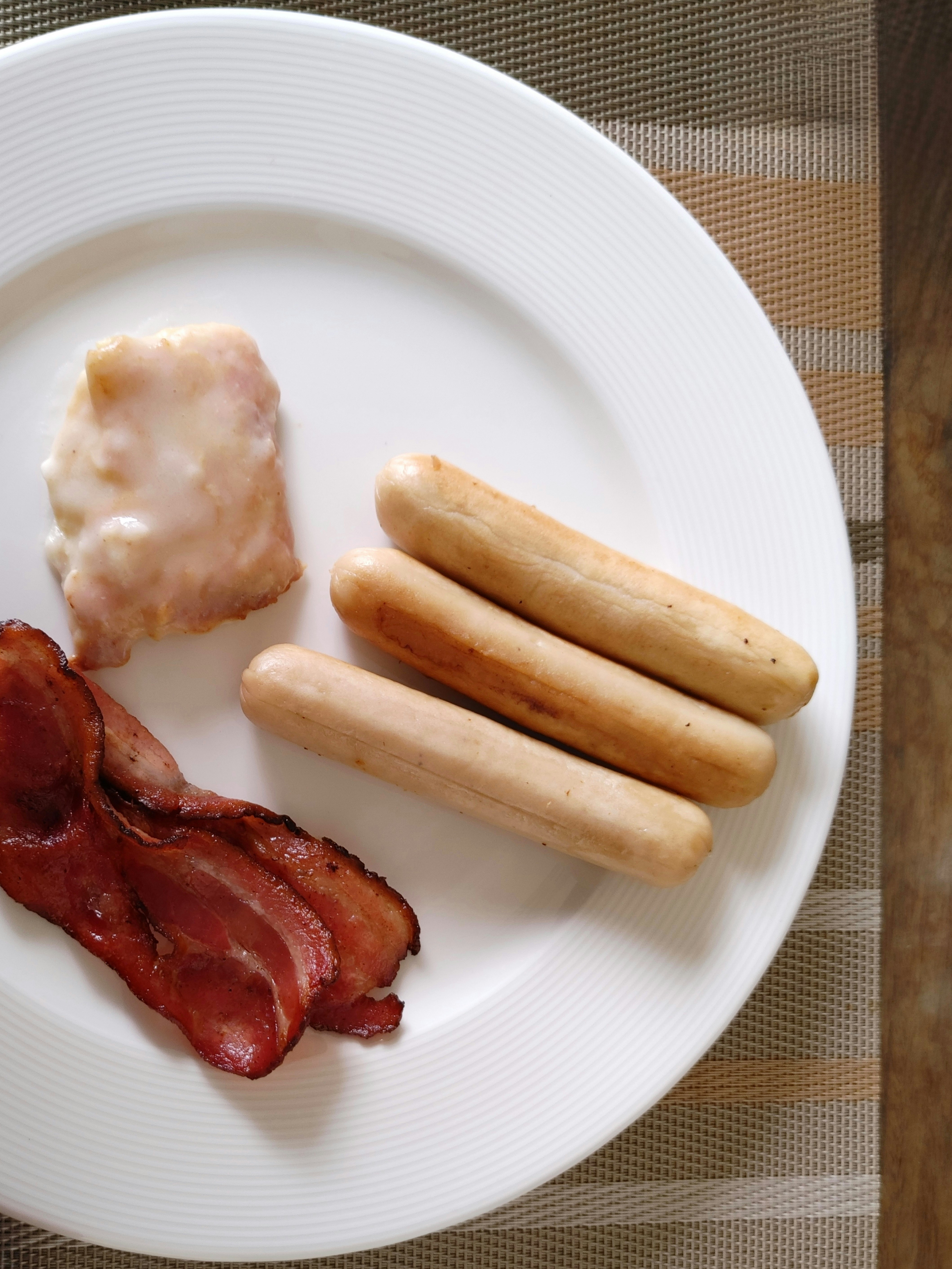 Plate of crispy bacon, knotted breadsticks, and a glazed square on a white plate