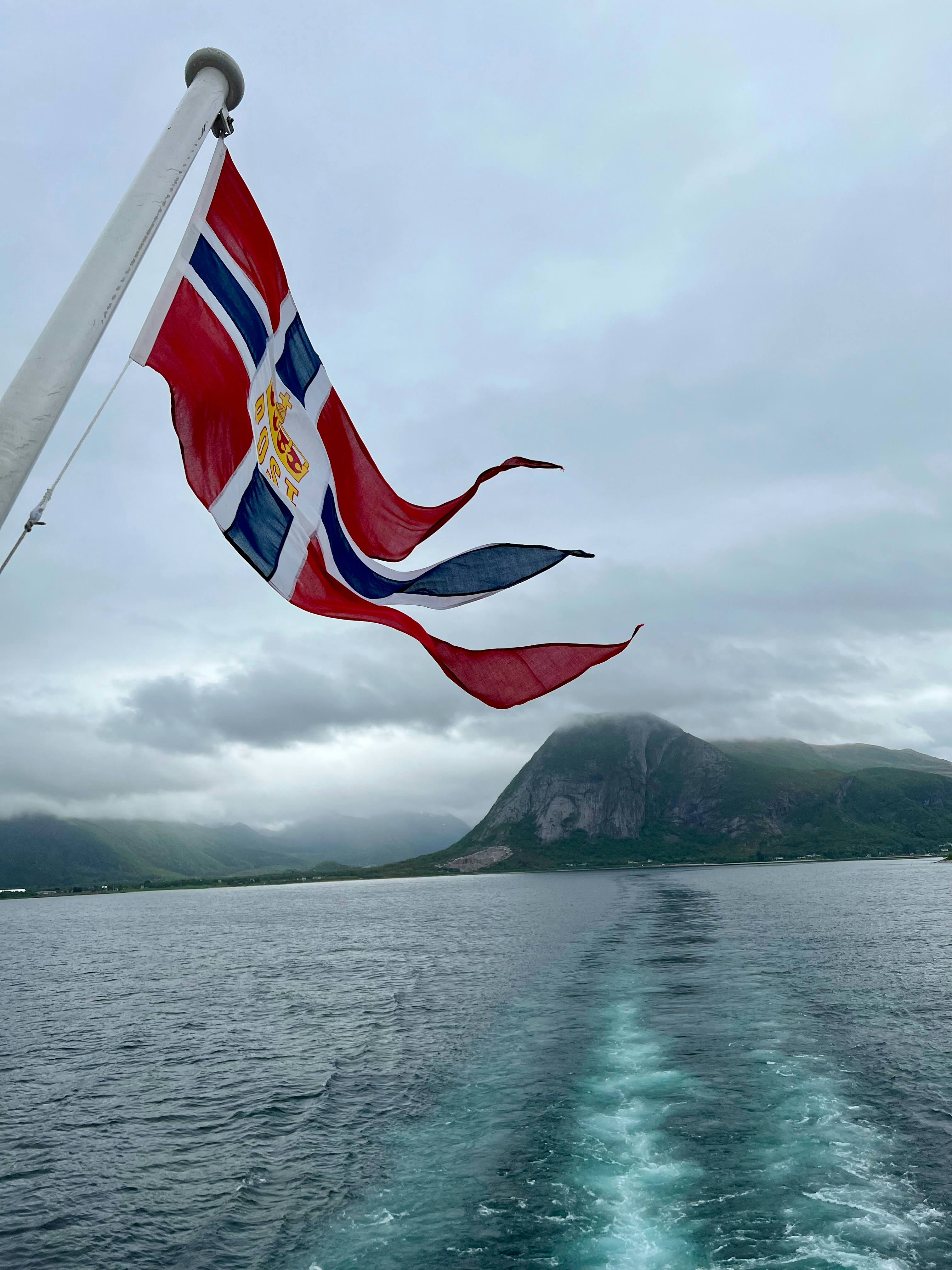 Flag Over Norwegian Fjord: A Journey Backlit by Wind
