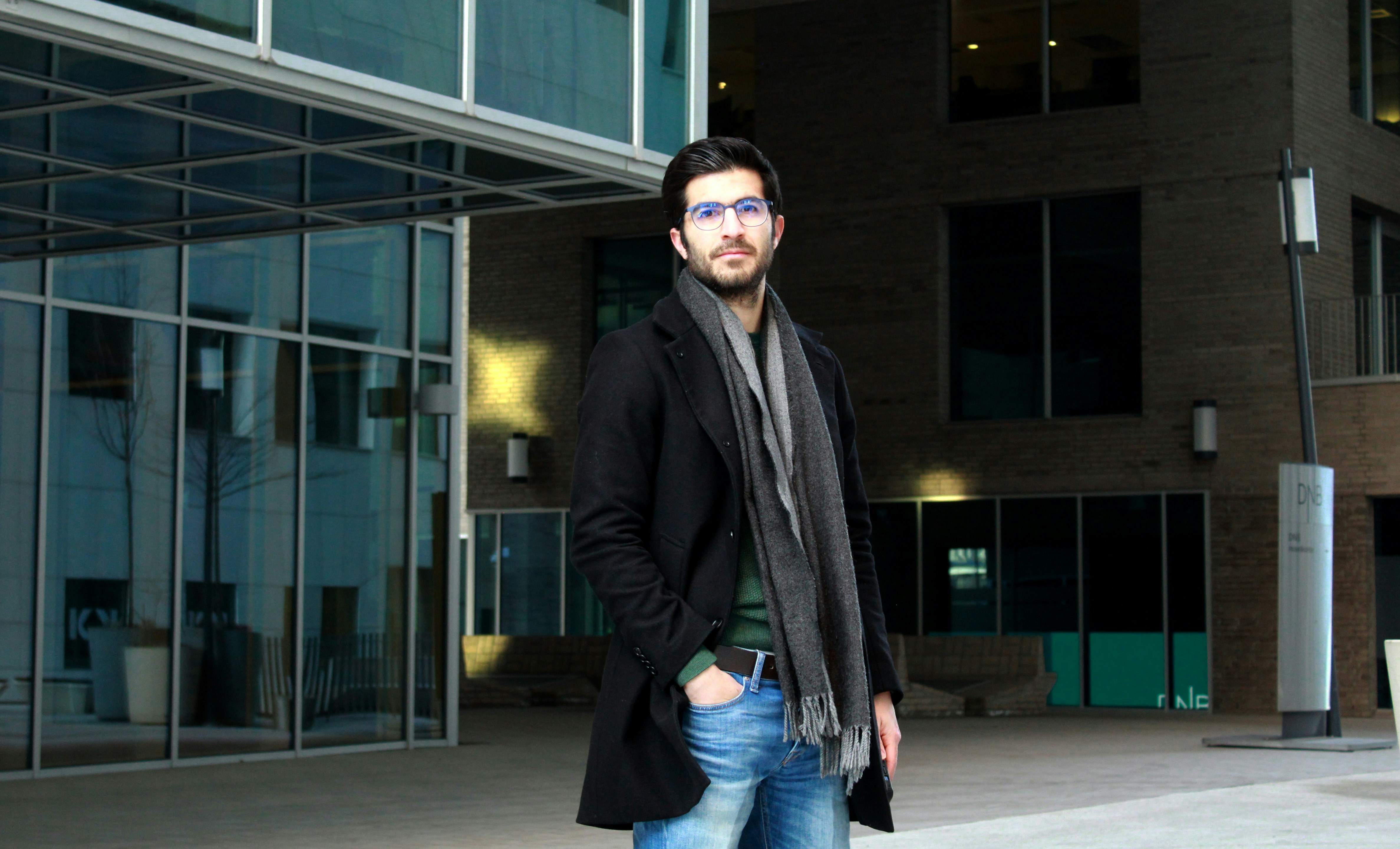 Urban Quiet: A Man in a Coat Anchored by Glass and Concrete