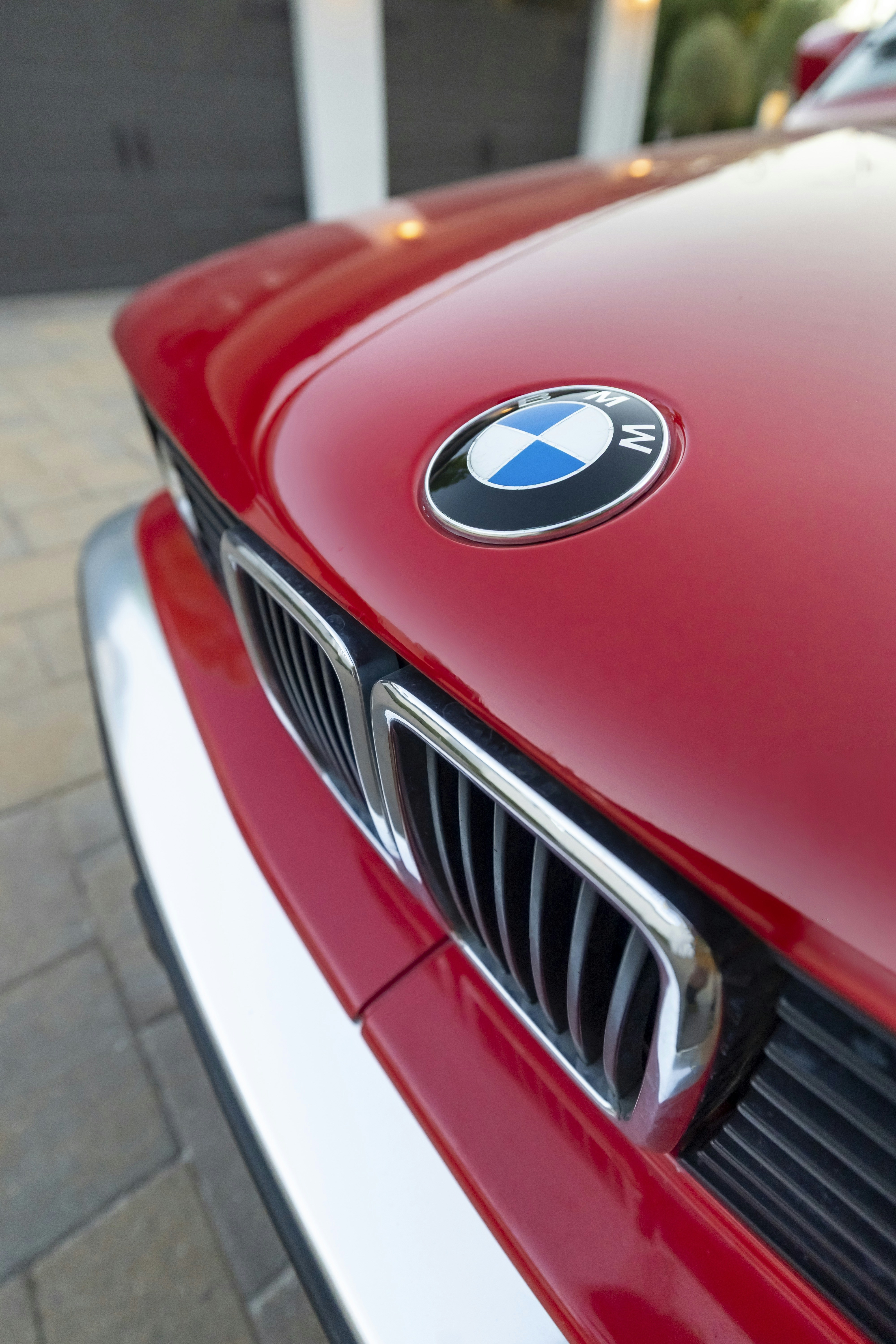 Red BMW emblem and grille close-up: chrome accents and glossy hood