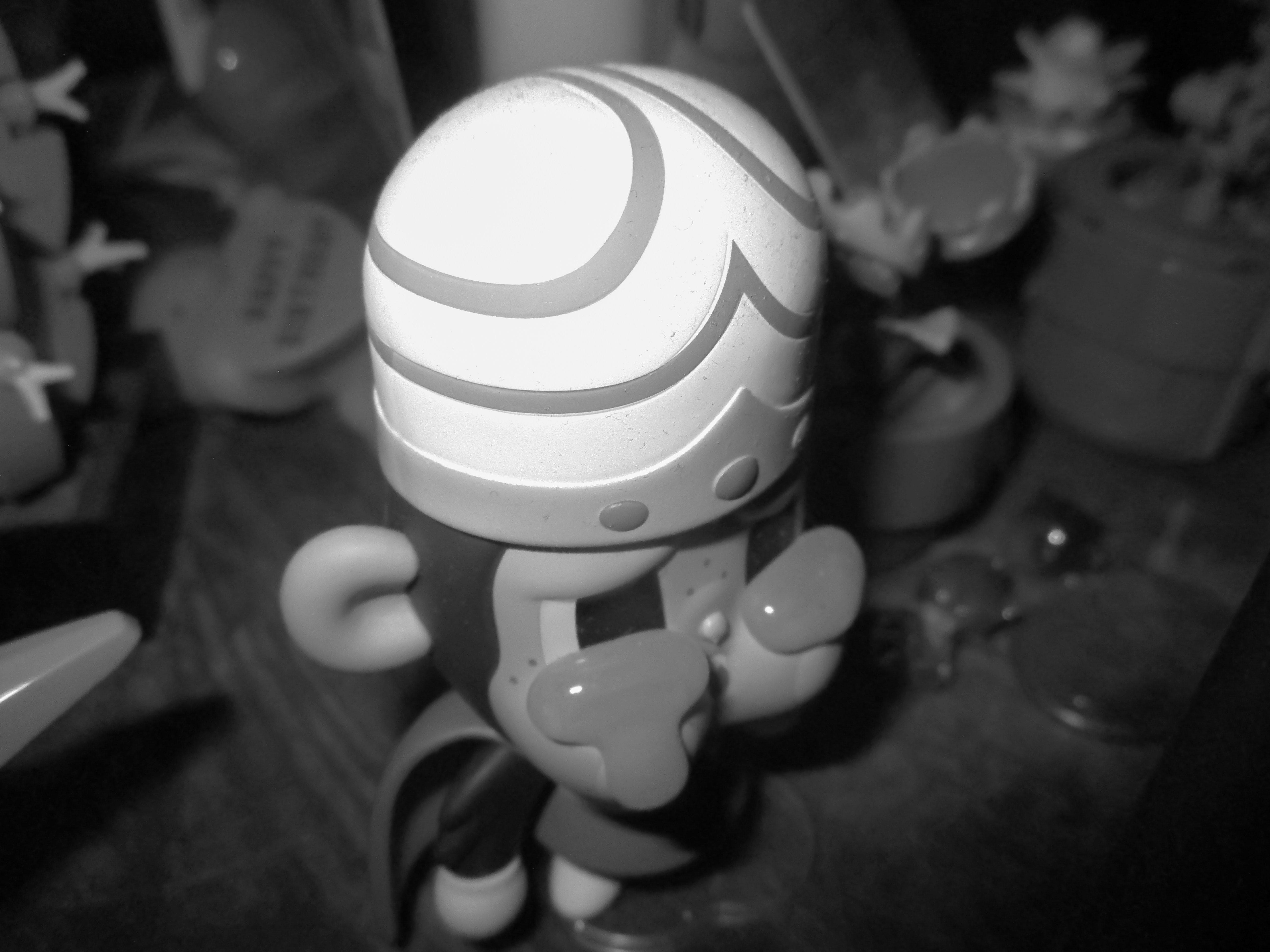 Toy figure under soft desk light, captured in grayscale