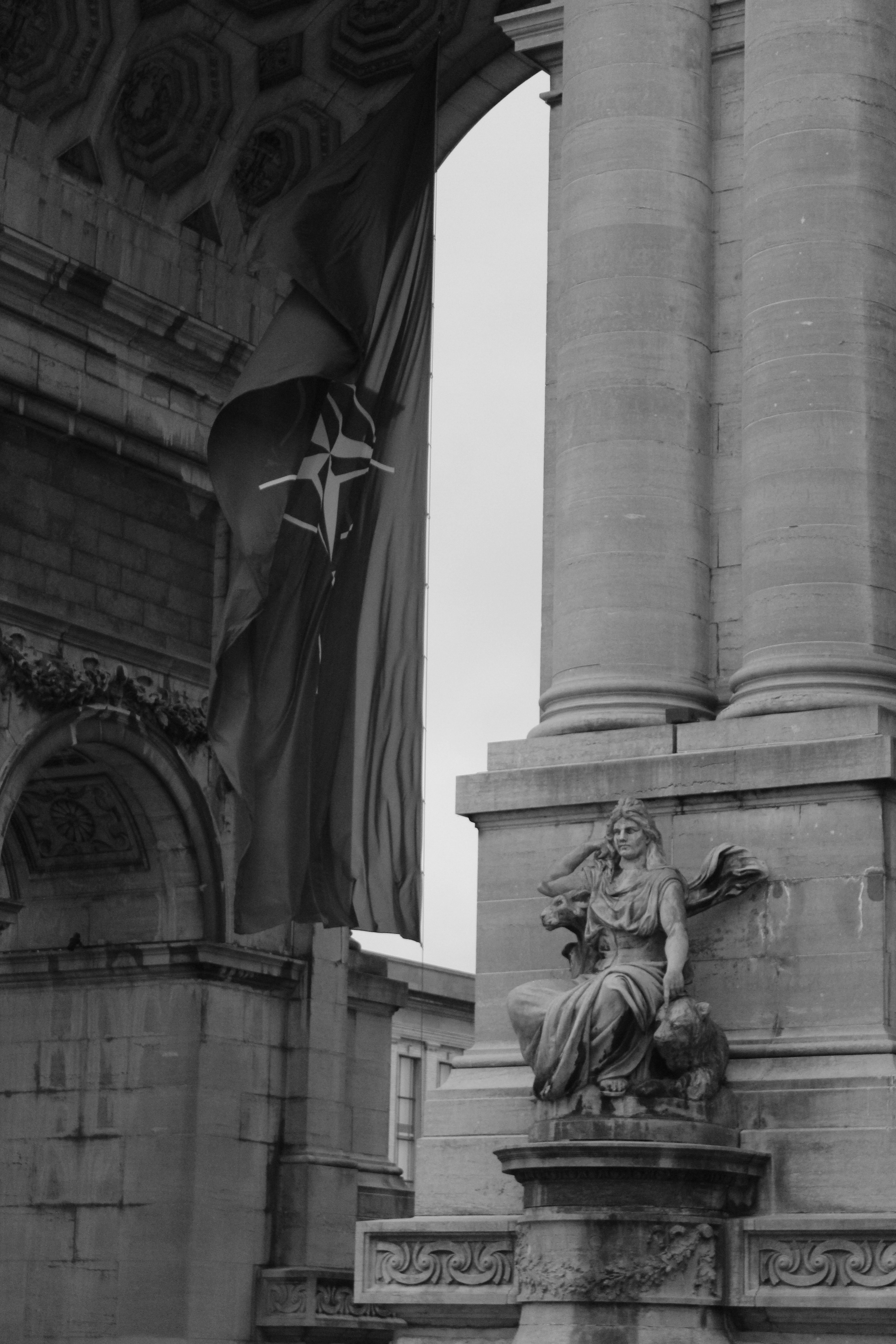 Stone Sentinel Beneath the Banner: A Quiet Frieze