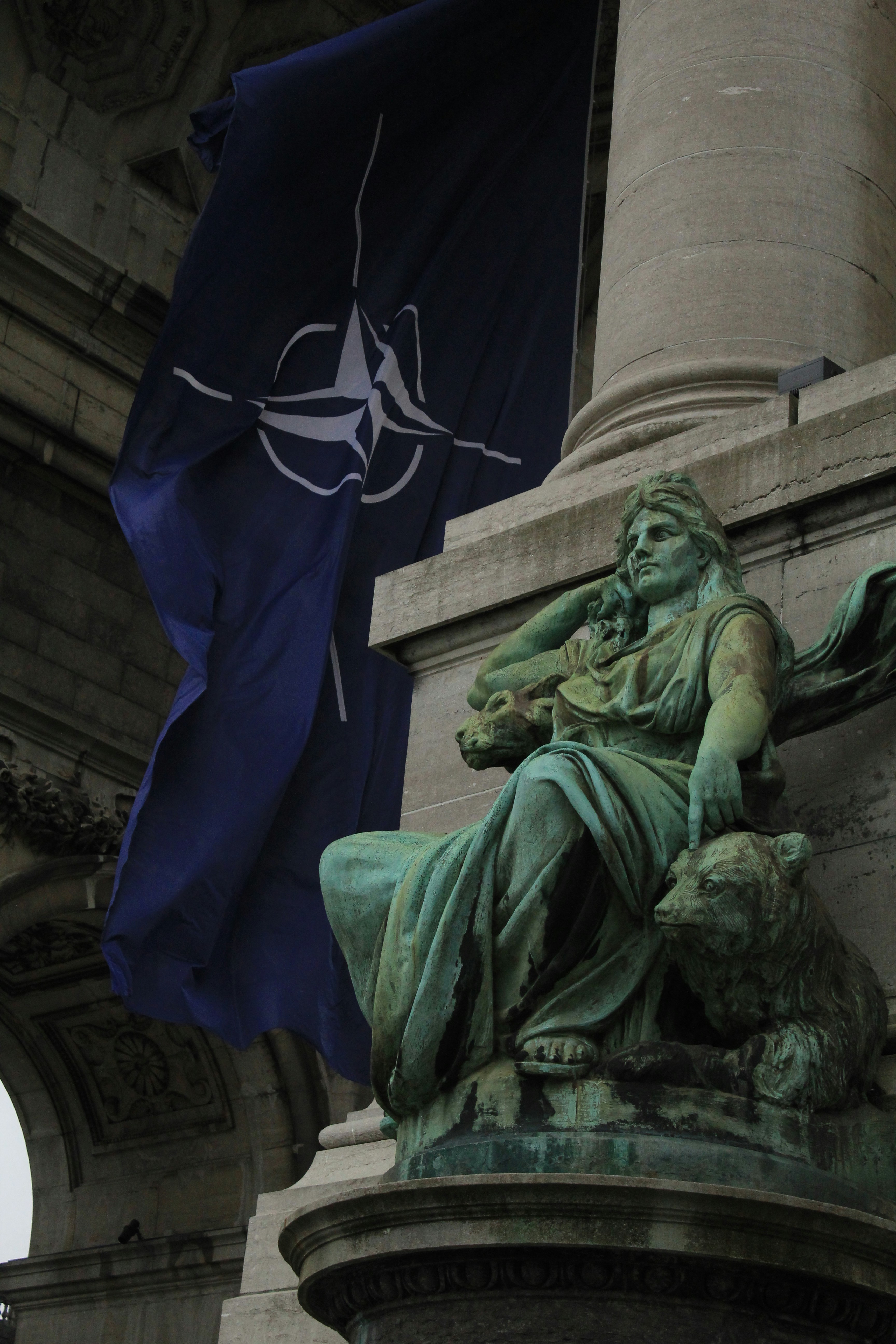 A Quiet Sentinel: Bronze Figure Meets a Close-Behind Banner