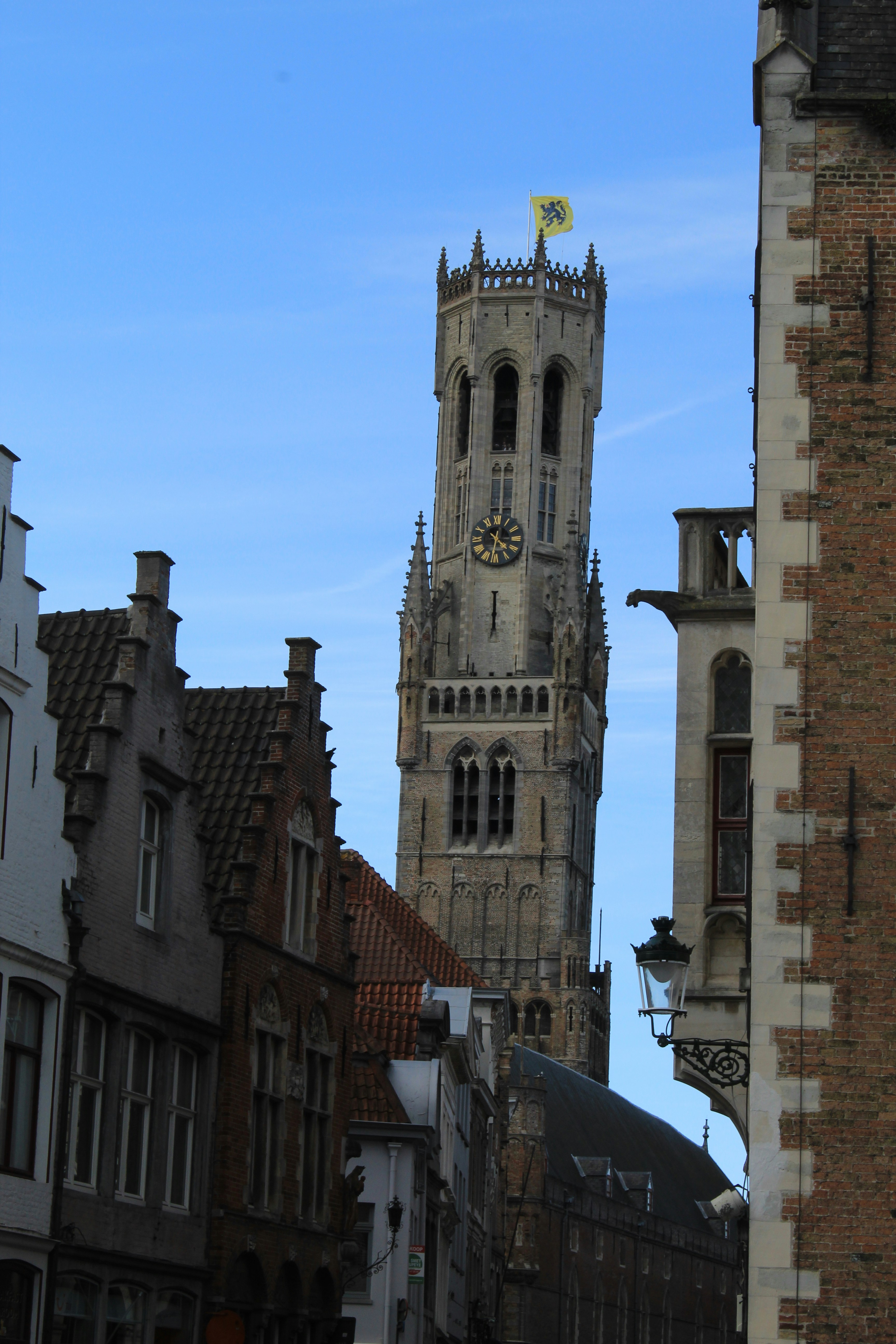 Clock Tower Rising Over Narrow Flemish Street