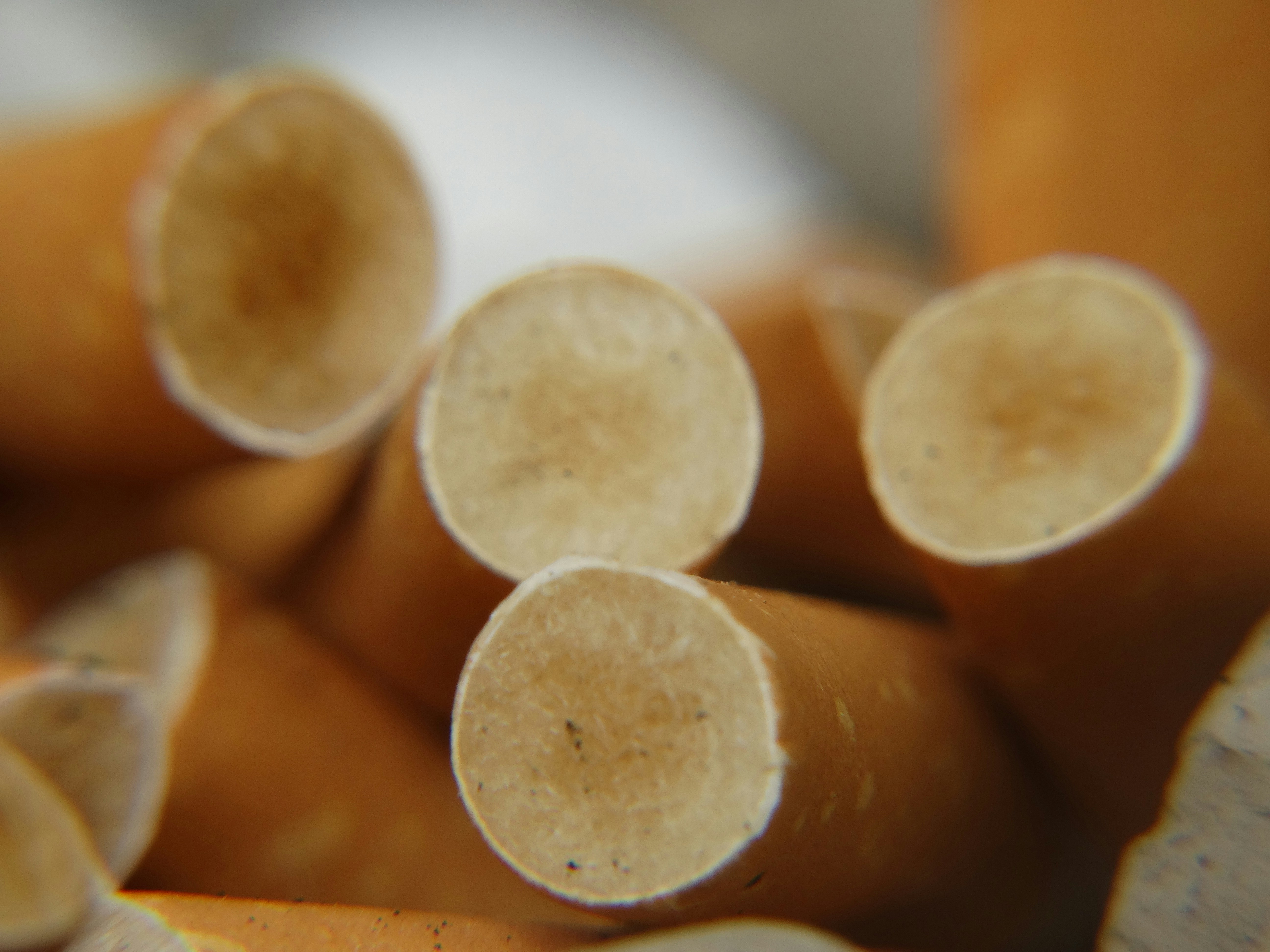 Cigarette-ends in a warm blur: an orange-tinted stack of hollow tubes