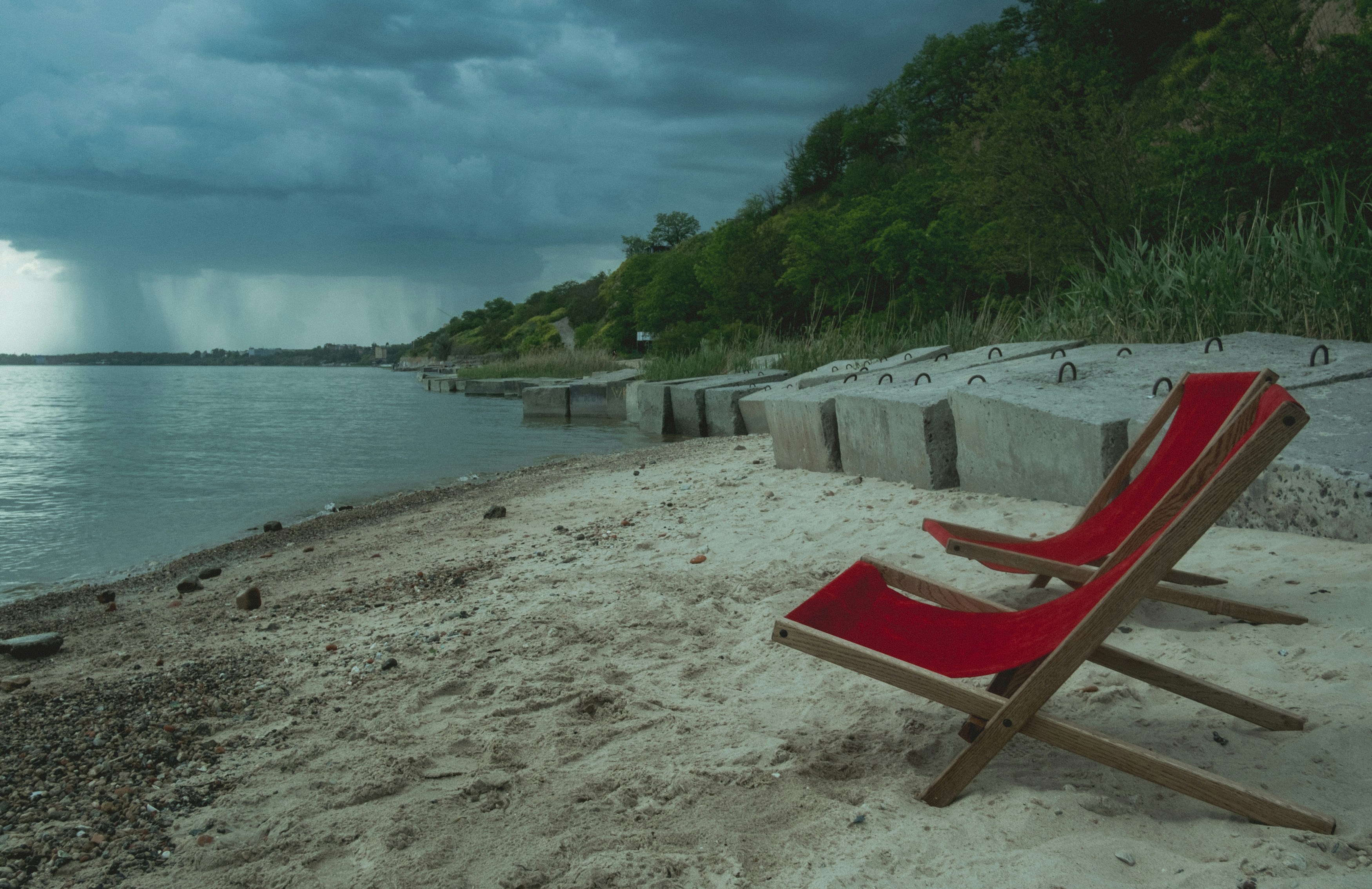 Red beach chairs on sand facing a stormy lake. photo – Free Summer ...