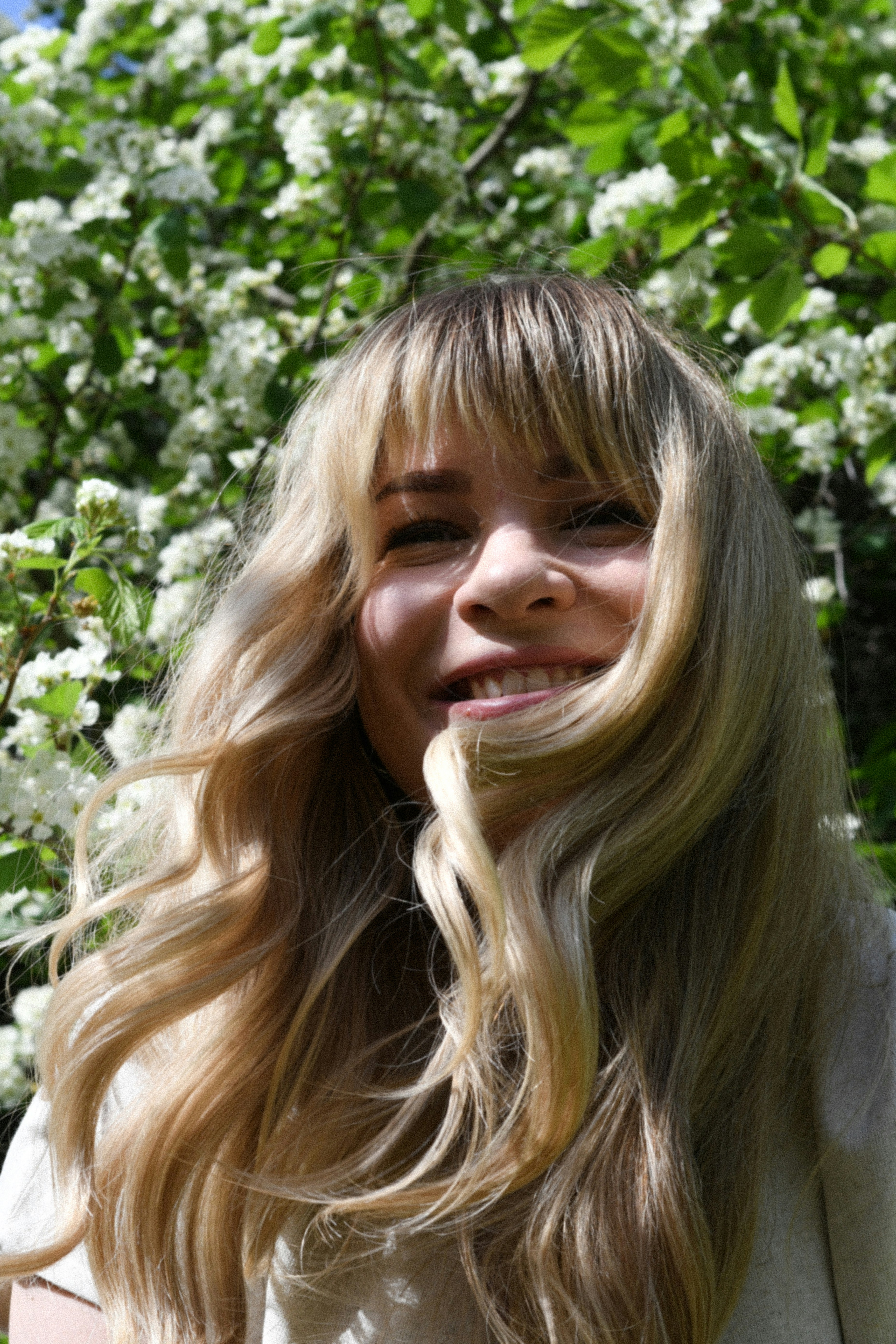 Sunlit Smile: Blonde Portrait Among White Blossoms