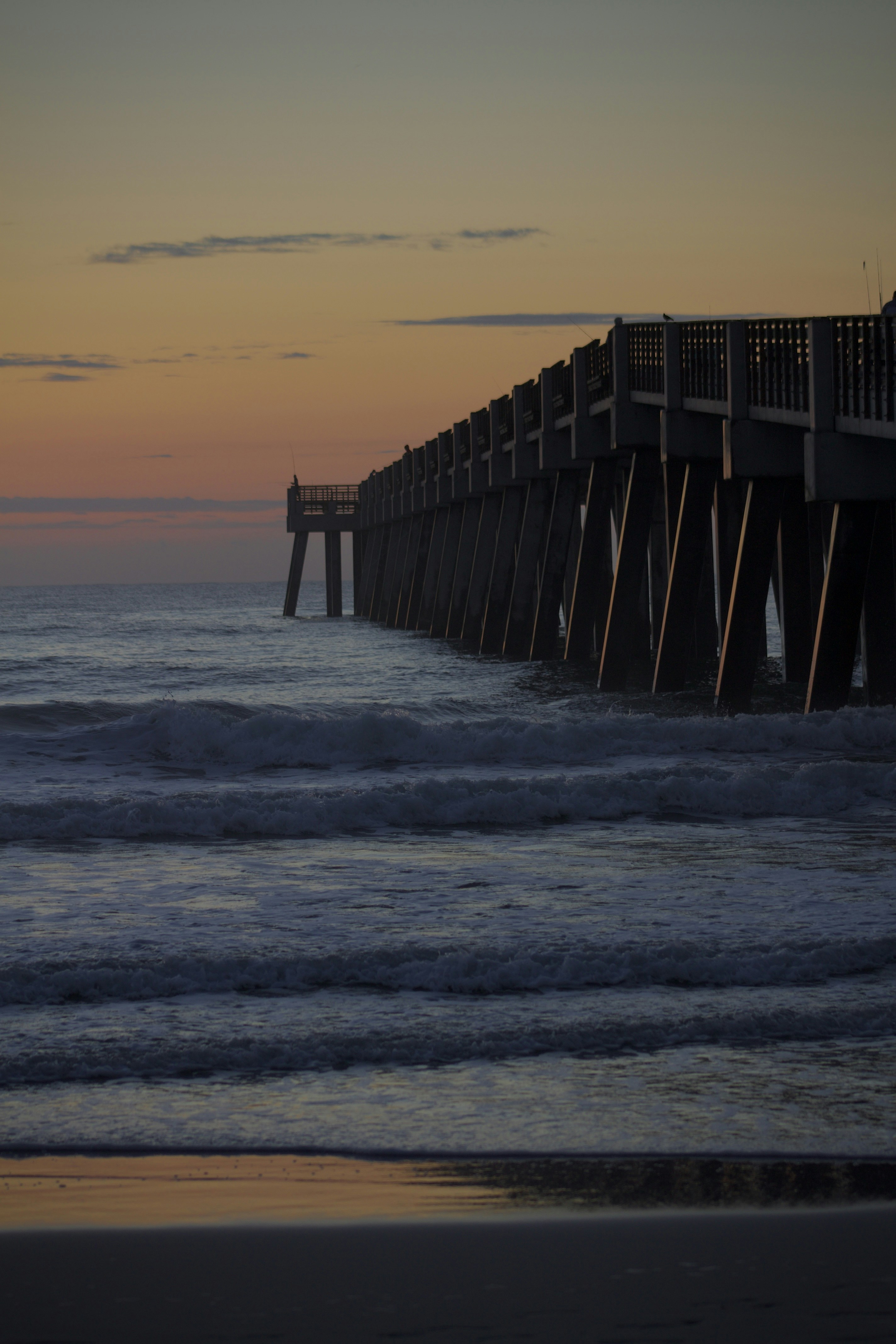 Pier silhouette at dusk: lines of stability over rolling tide