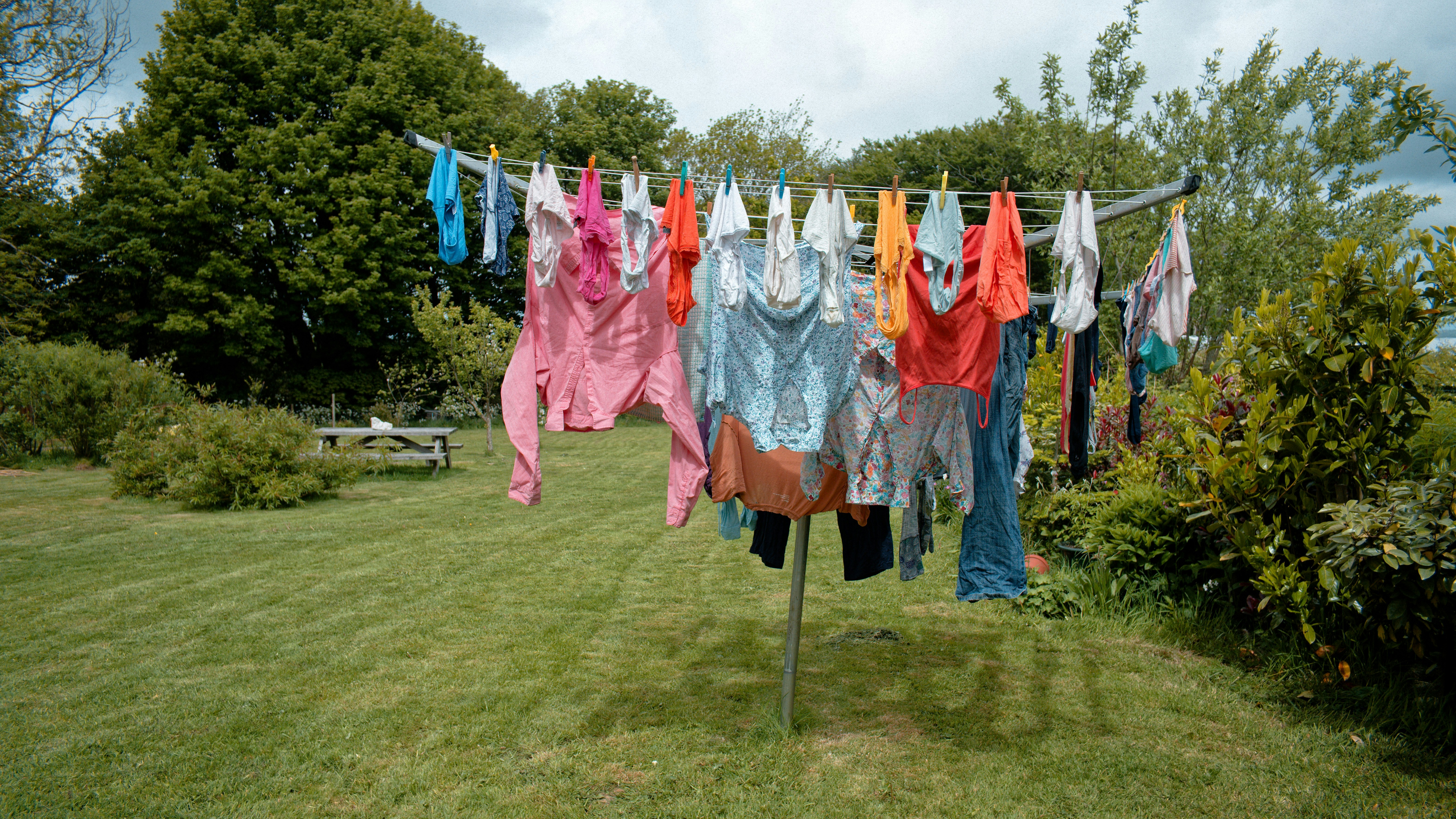 Colorful laundry on a sunny afternoon: garments fluttering above a quiet lawn