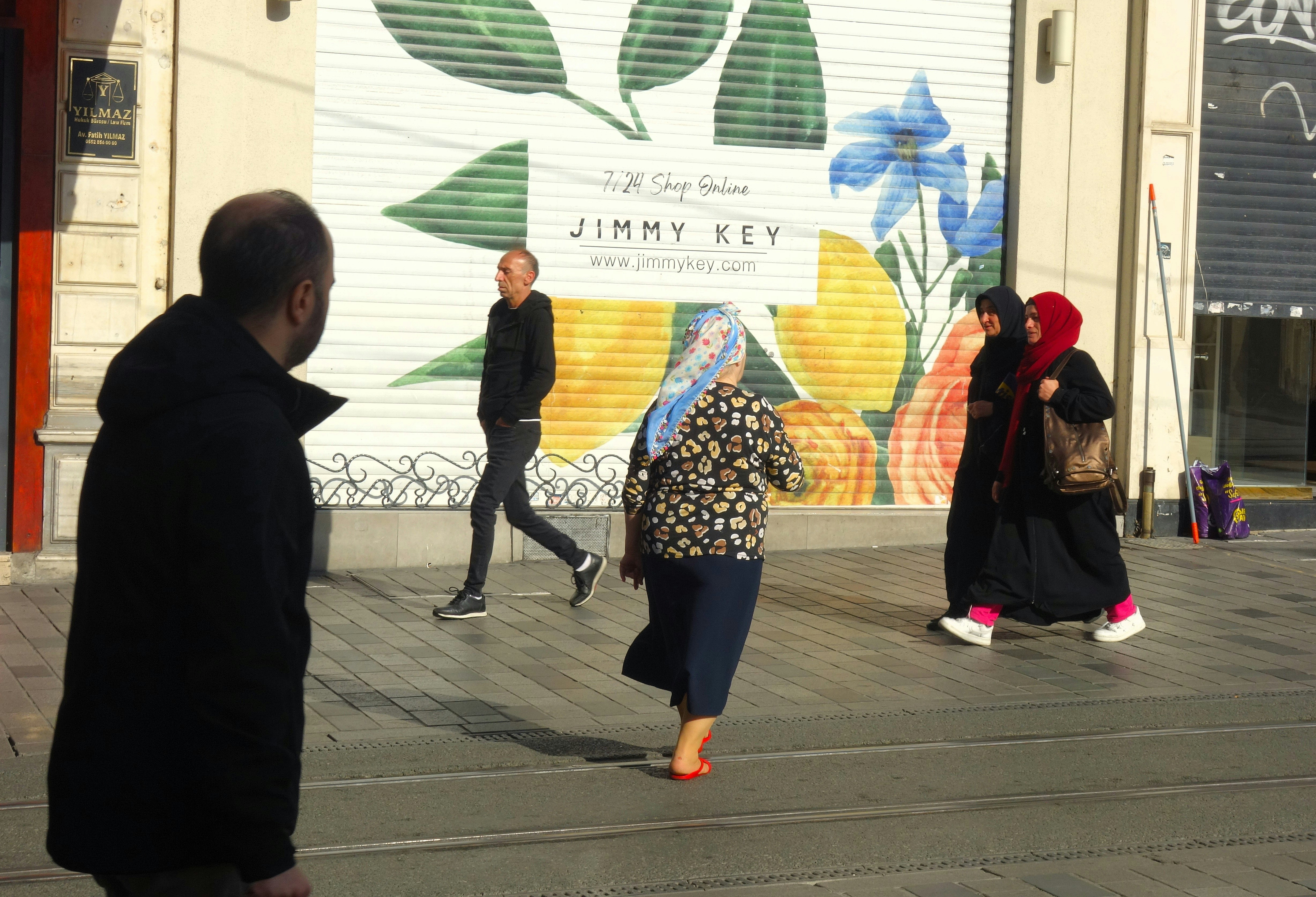 Crosswalk Pulse: Street Scene with Moving Figures and a Floral Mural