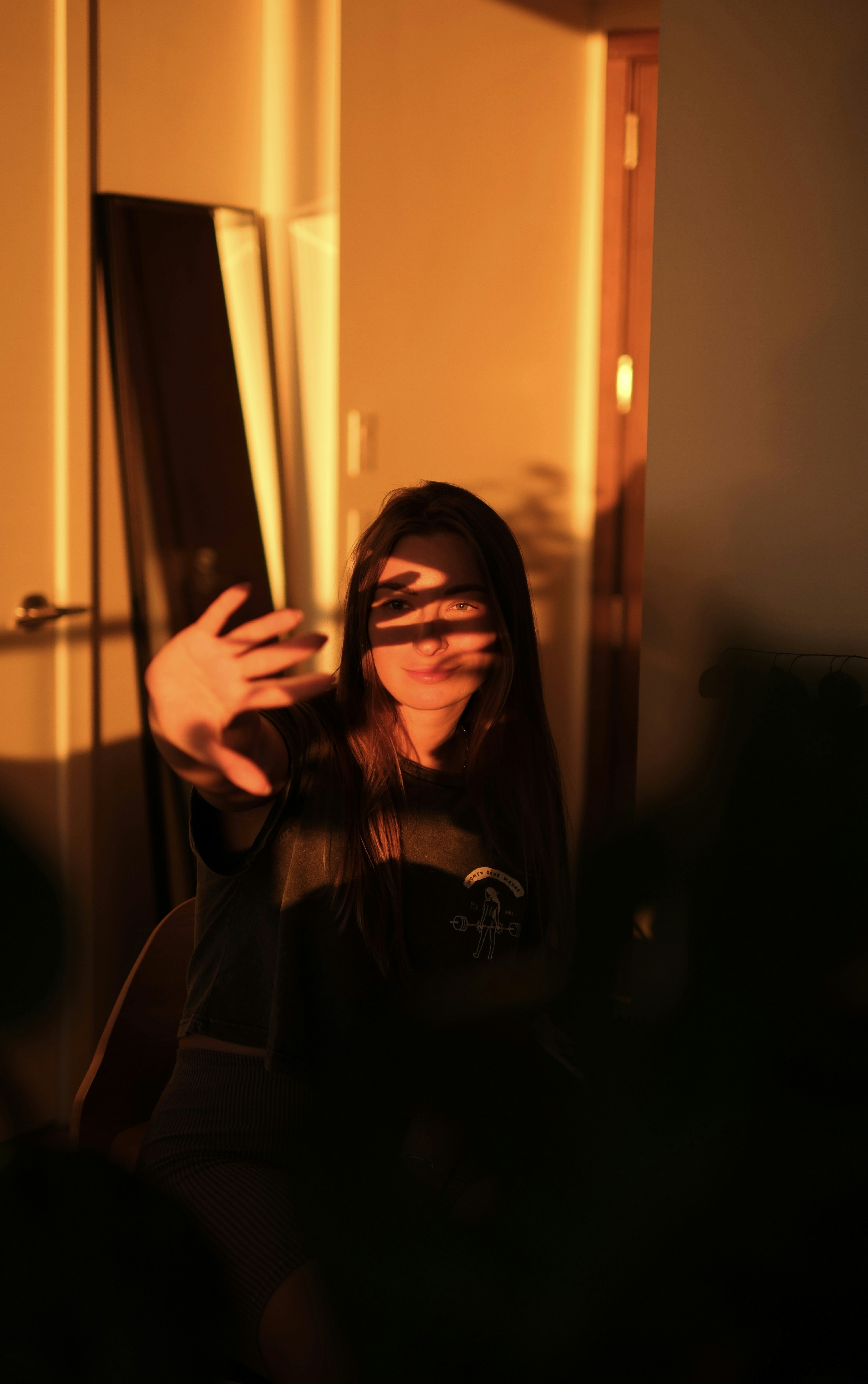 Shadowed Glimpse: A Girl Reaches Through The Warm Doorway Light