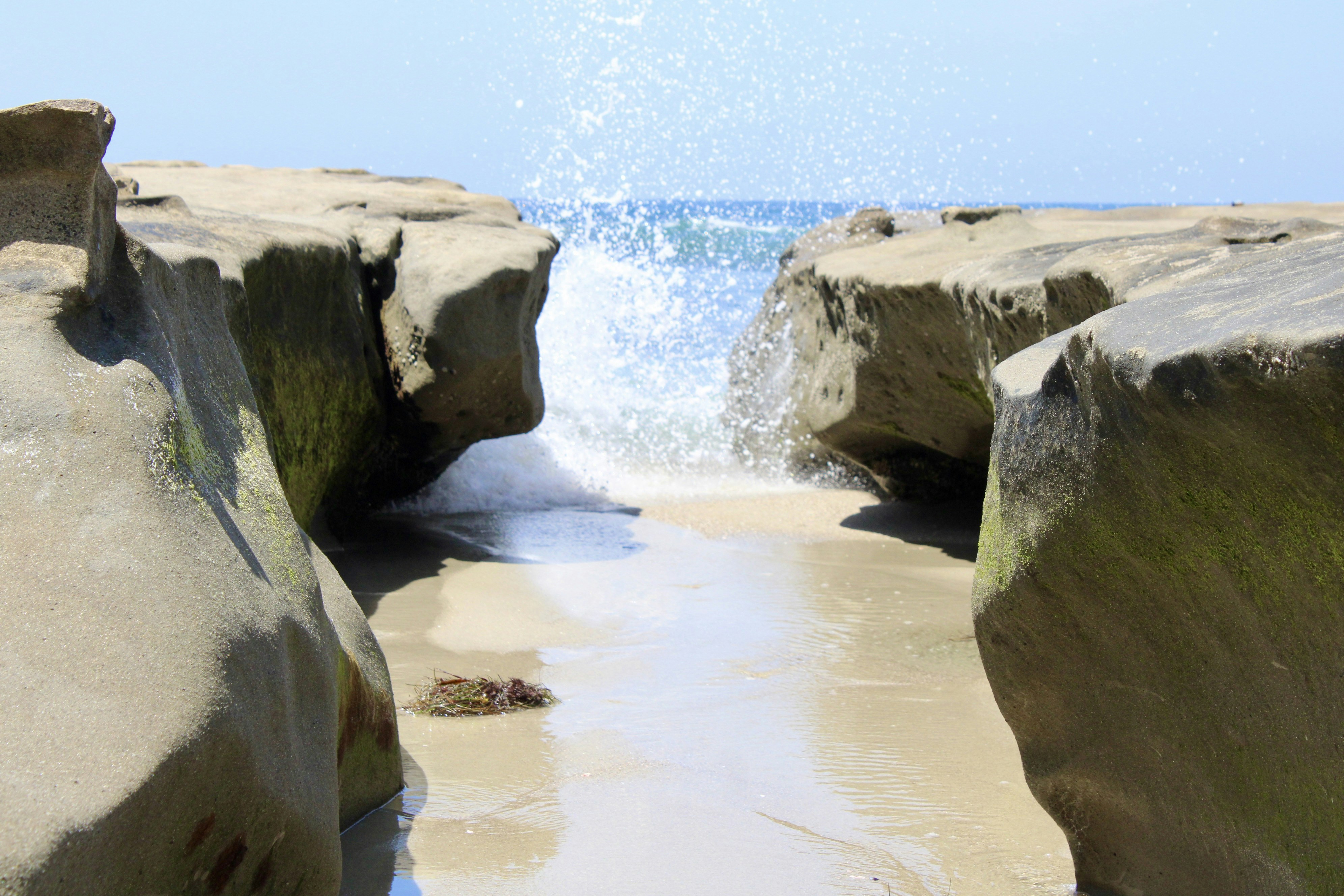 Crescent Passage: Sunlit Beach Between Weathered Cliff Faces