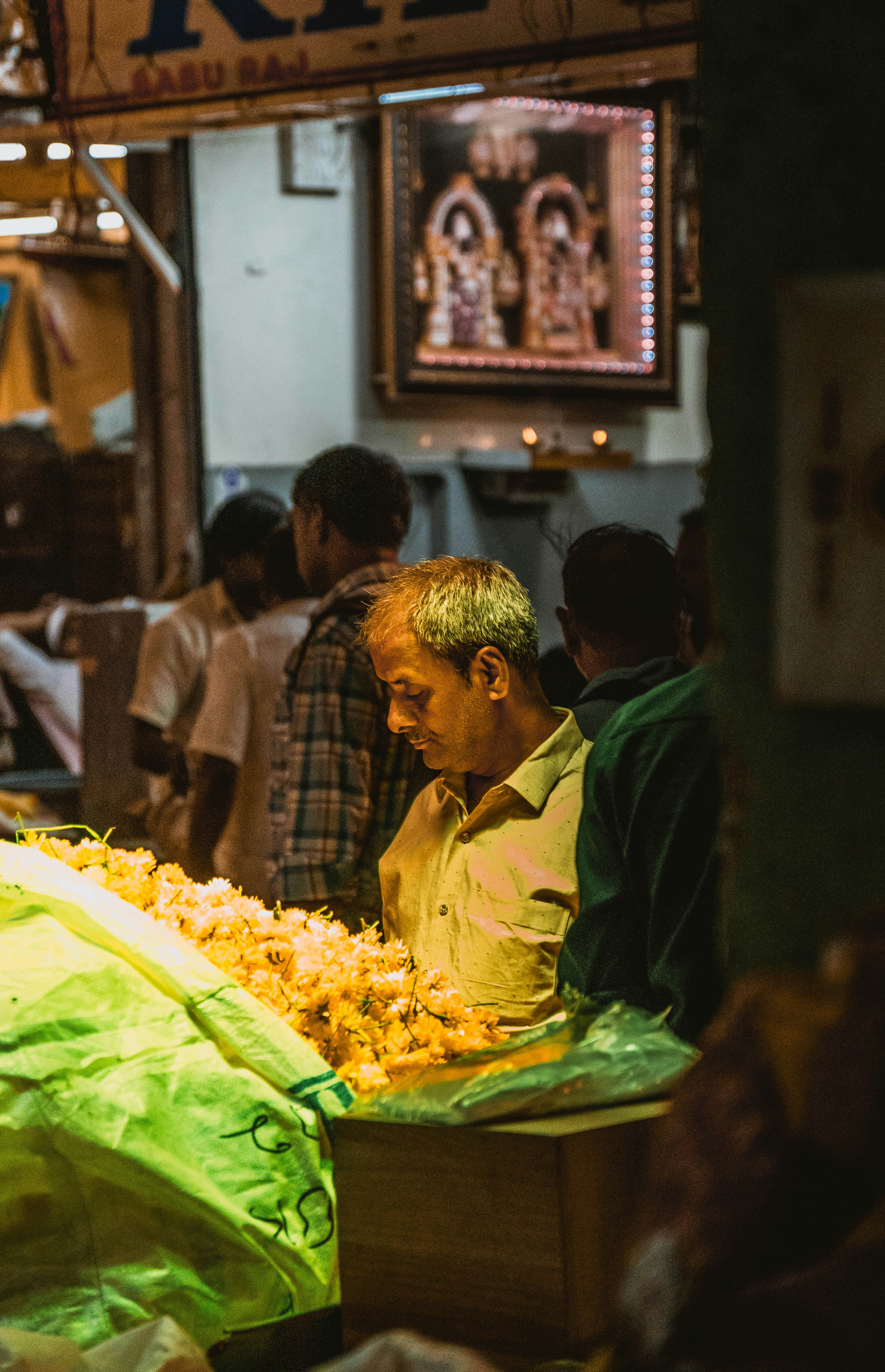 Golden Night Vendor: A Portrait of Focus Amid a Busy Market