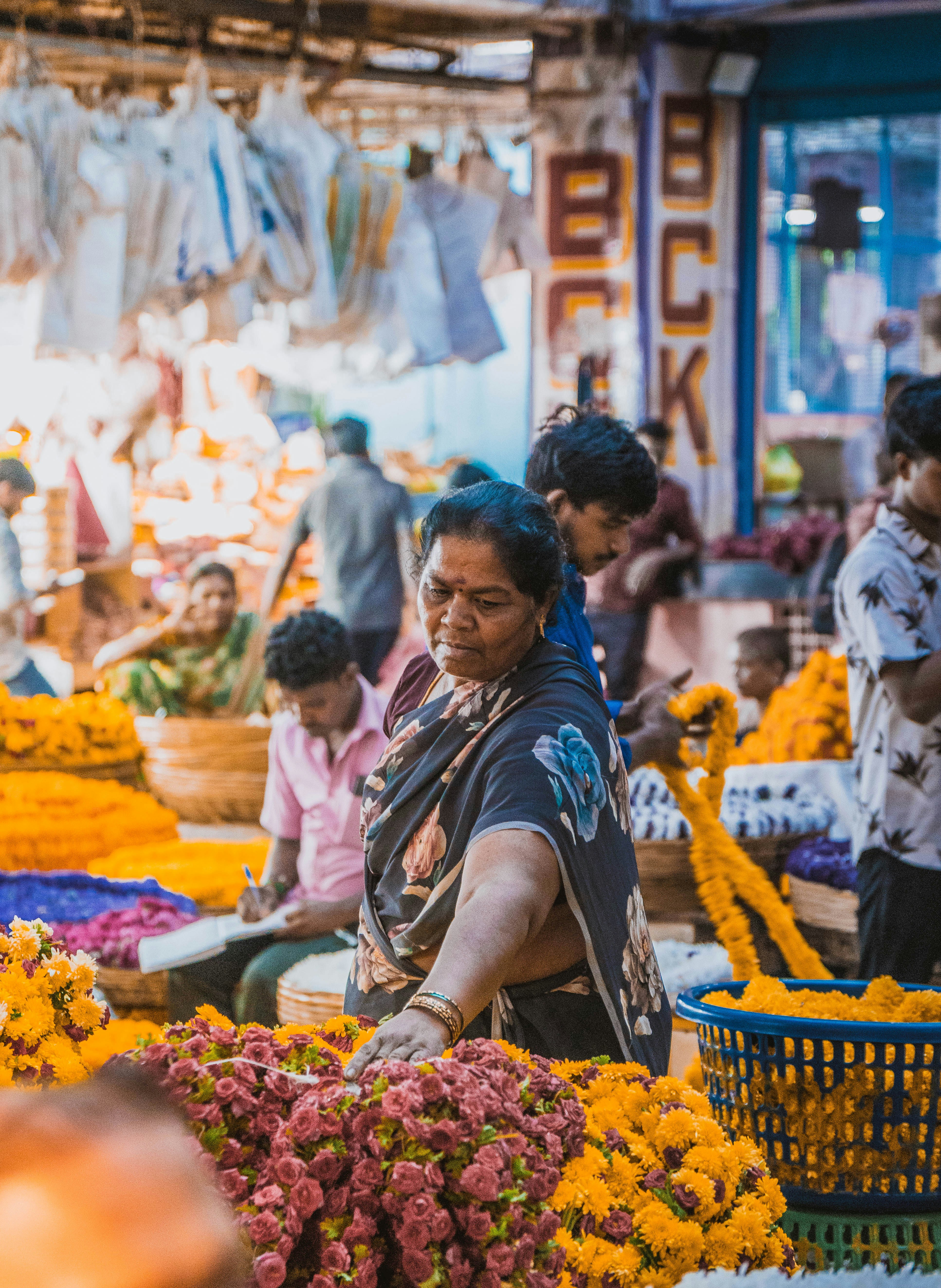 At the Floral Stall, a Woman Weighs a Moment of Color