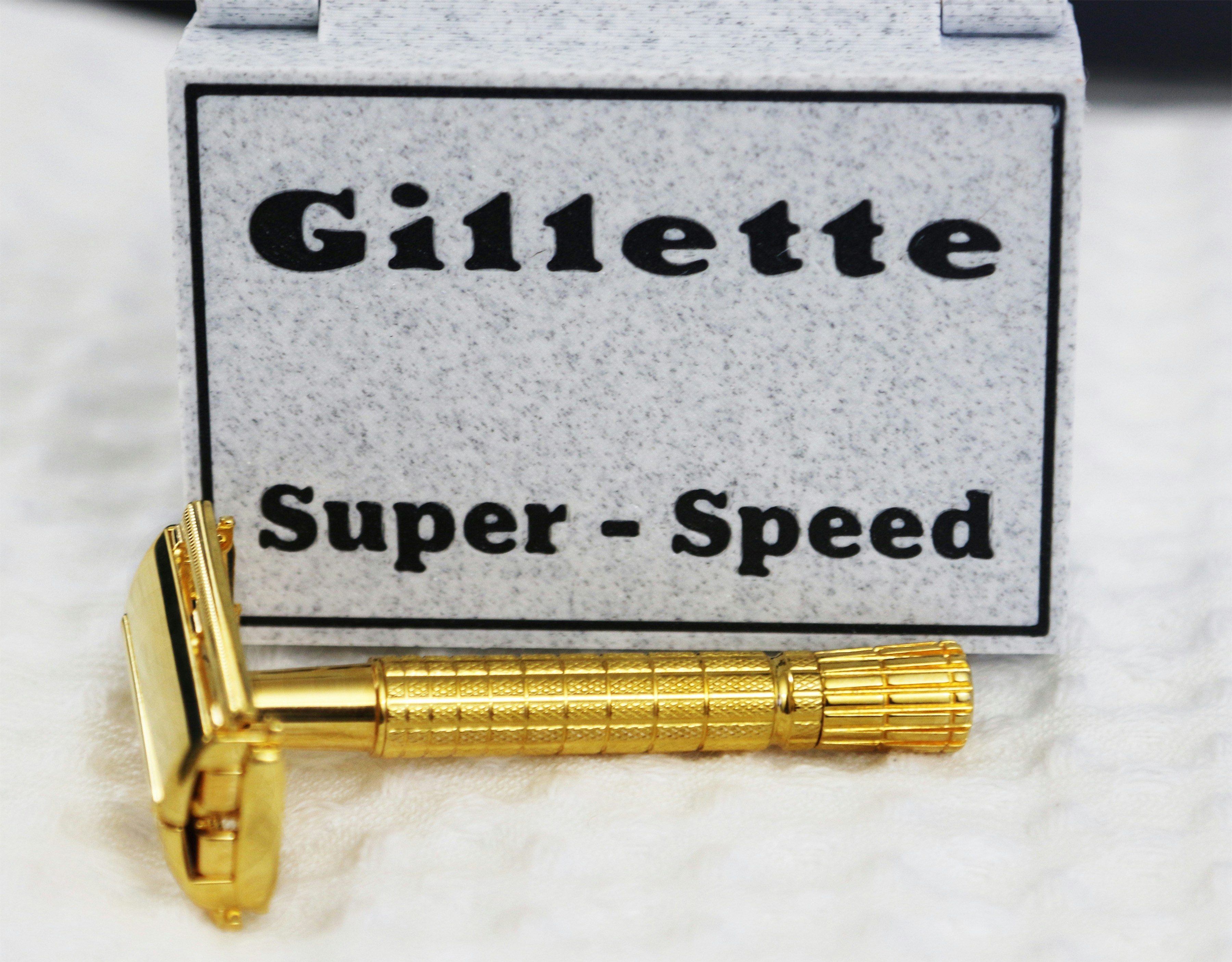 Close-up of a vintage Gillette razor blade box with a gold safety razor resting beside it