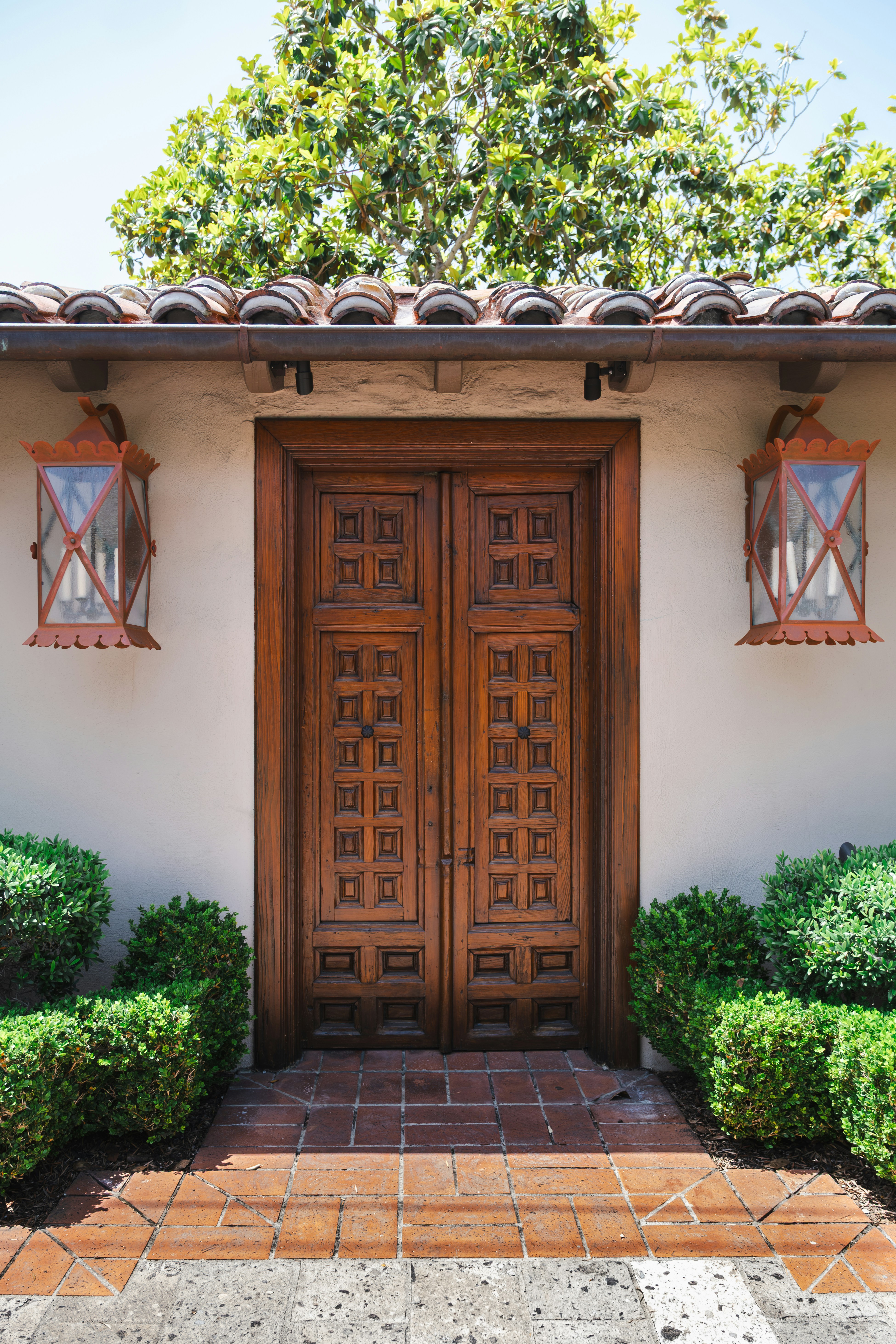 Carved Wooden Doorway Framed by Lanterns and Emerald Foliage