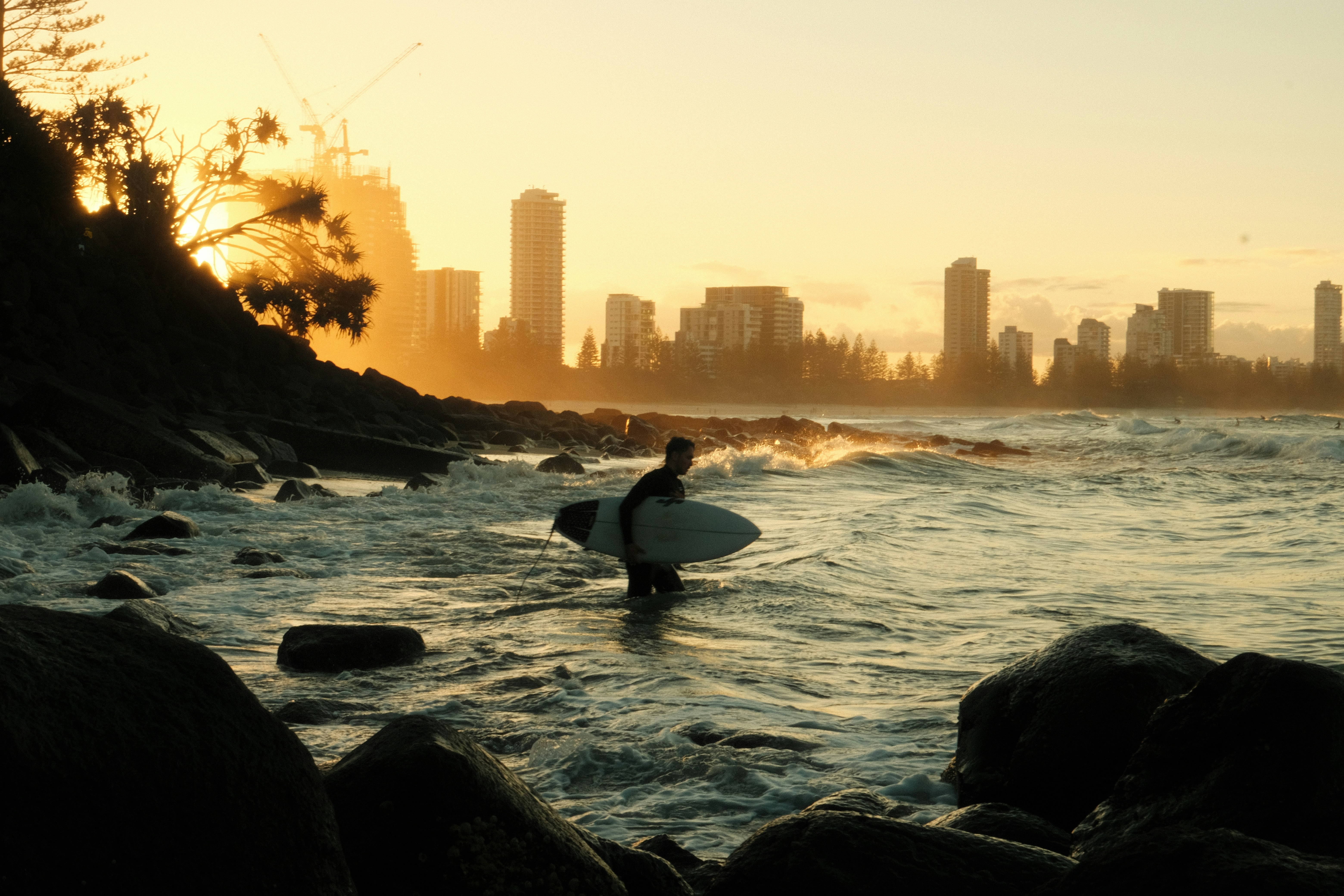 Surf on the Golden Hour: A lone skimmer by the city horizon