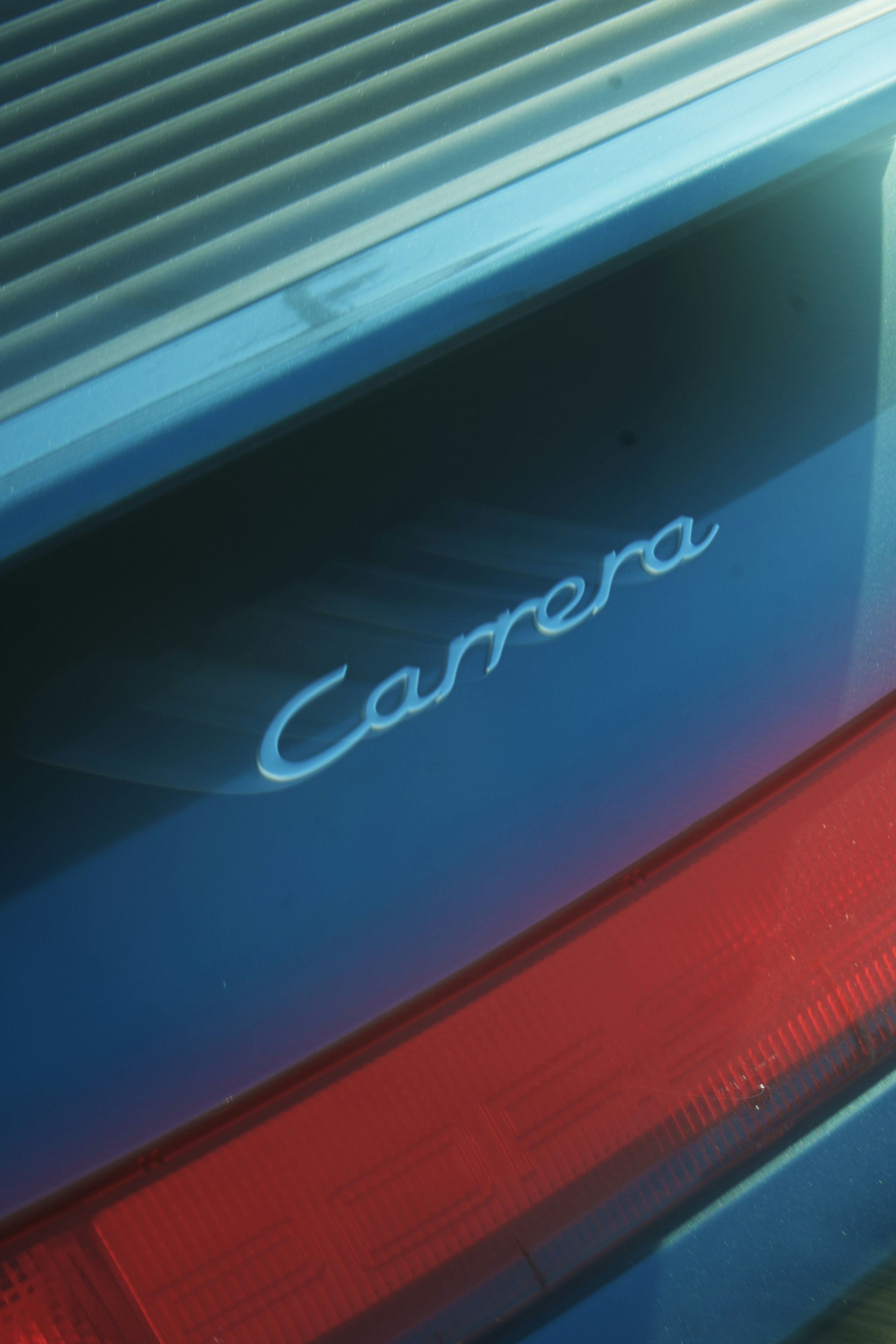 Blue-tinted Car Emblem: Carrera Script Reflected on Tail Light