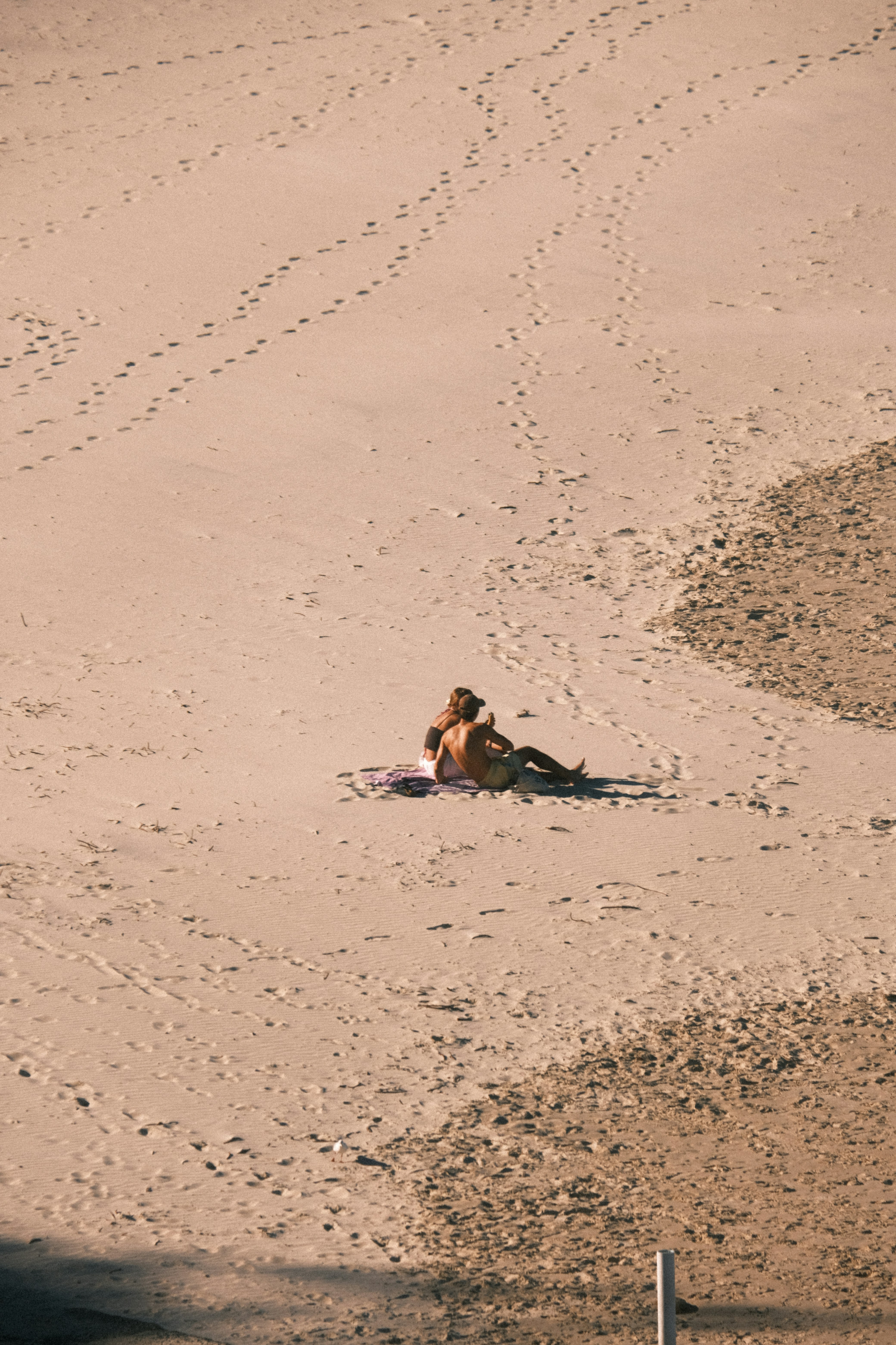 Solitary Moment: Beach Couple Embrace in Quiet Sand