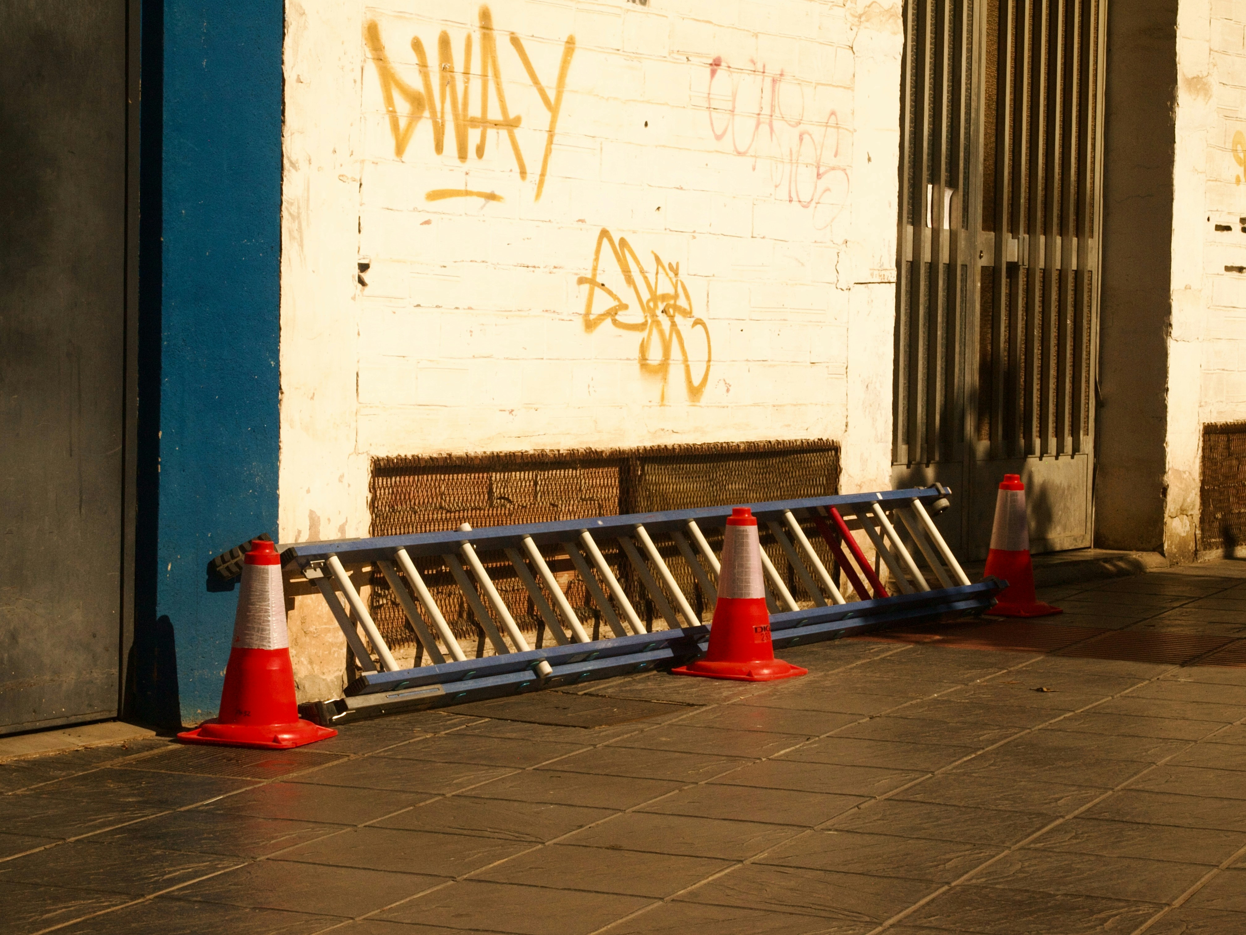 Ramp of Confinement: a street-scene scaffold and barrier on a graffiti-stained wall