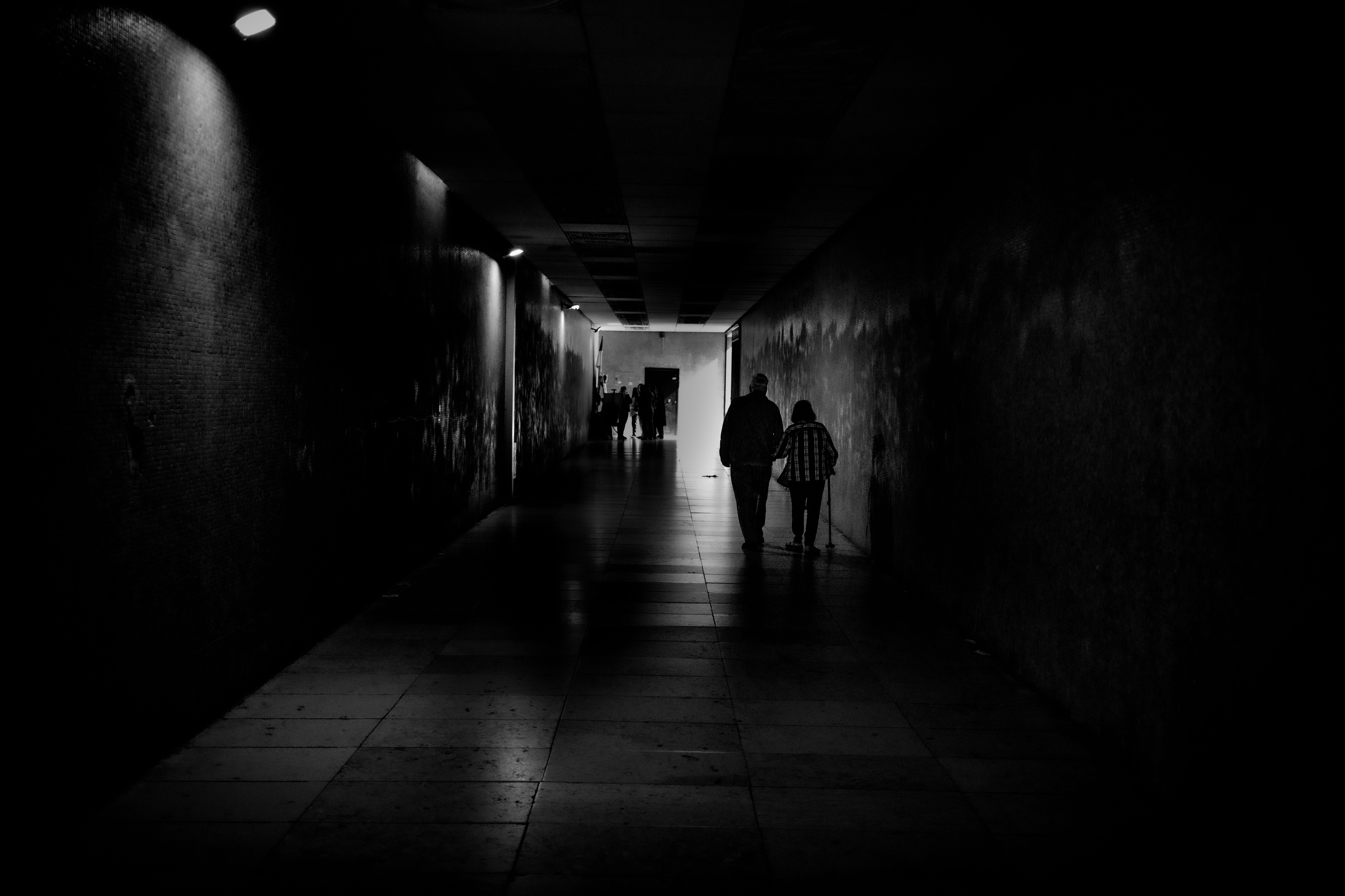 Silhouette Walkers in a Dim Subway Tunnel