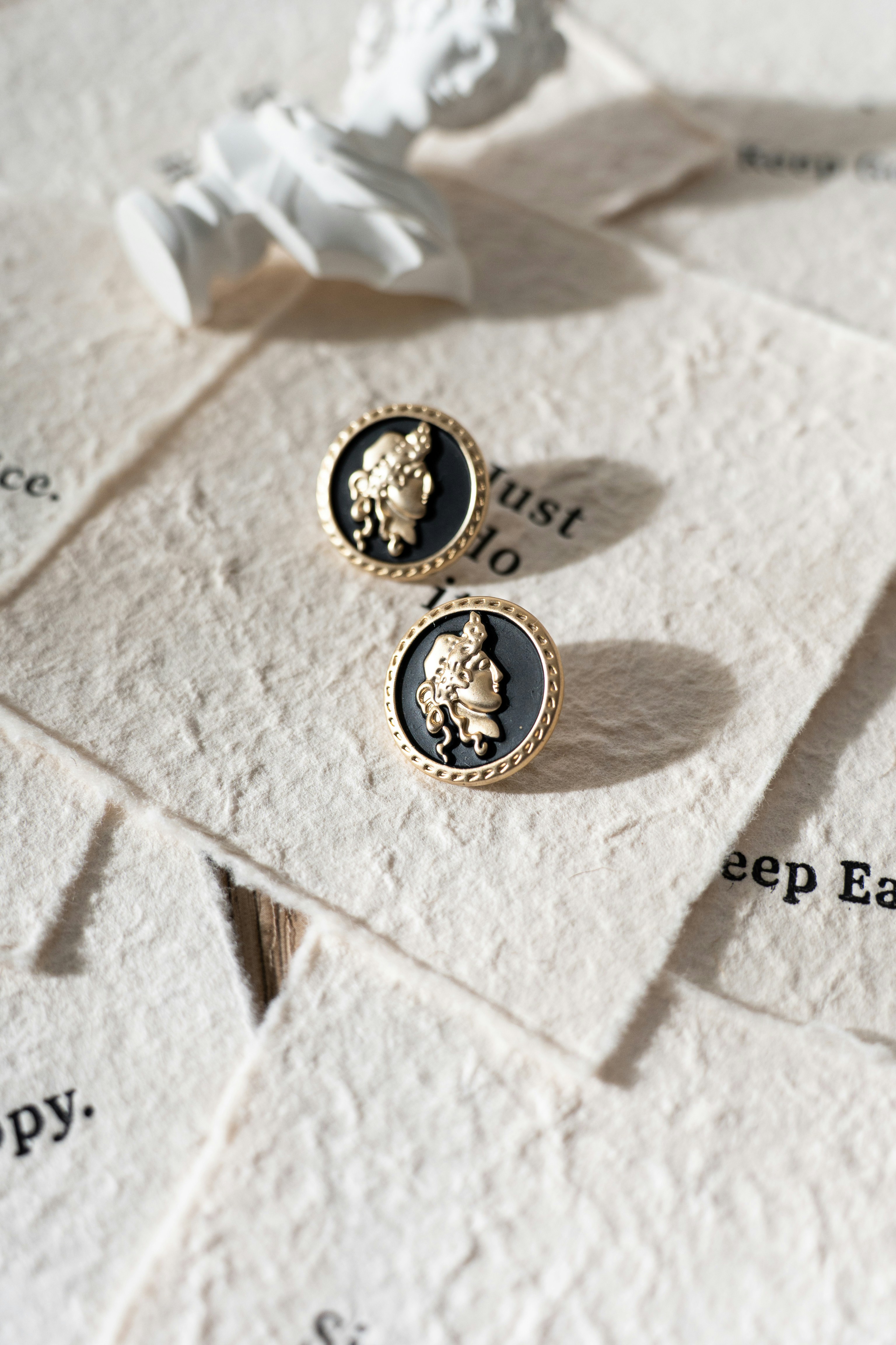Gold-on-Black Cufflinks Resting on Frayed Paper