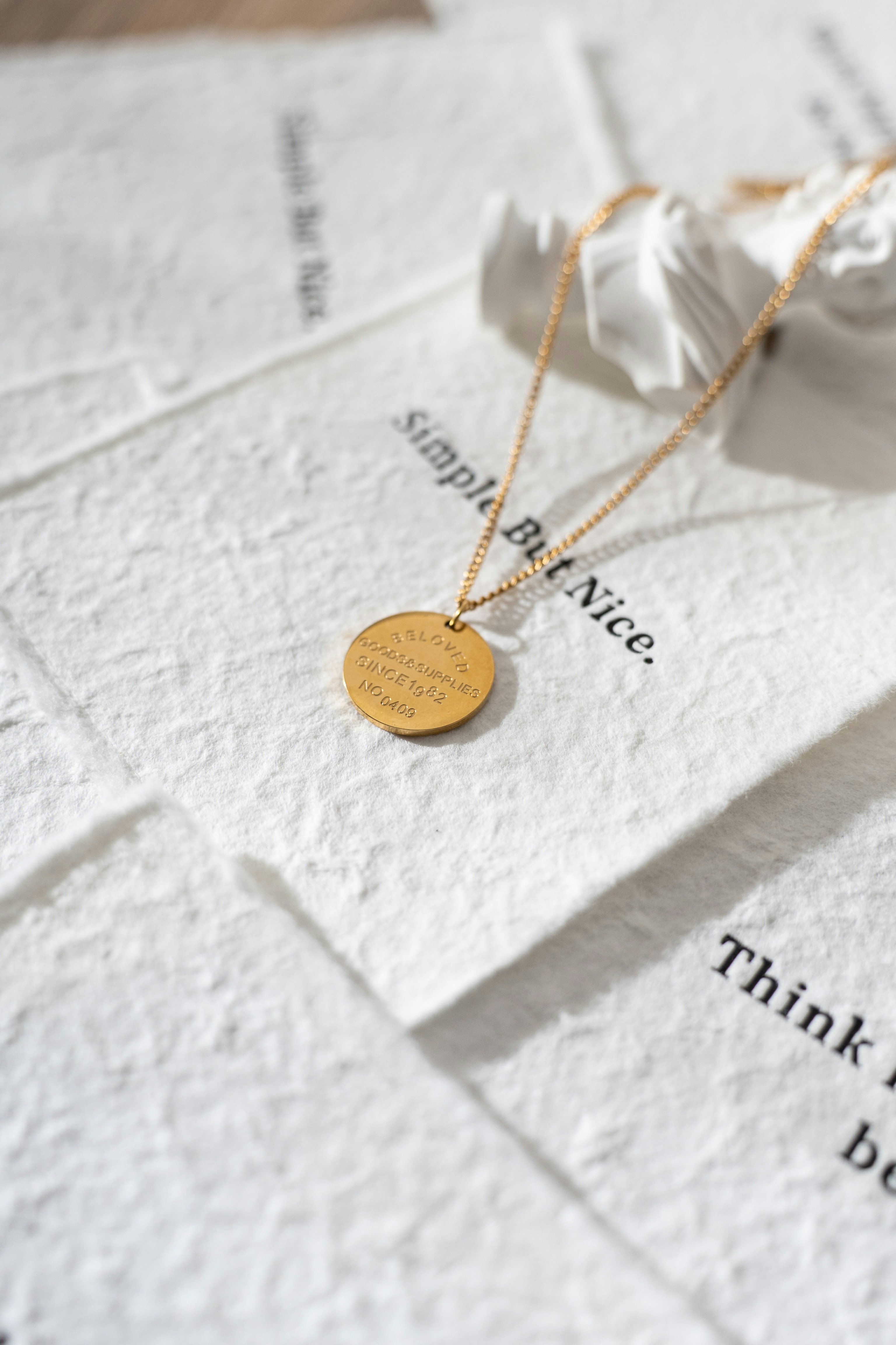 Gold Necklace Pendant Resting on Crumpled Paper: Quiet Minimalism