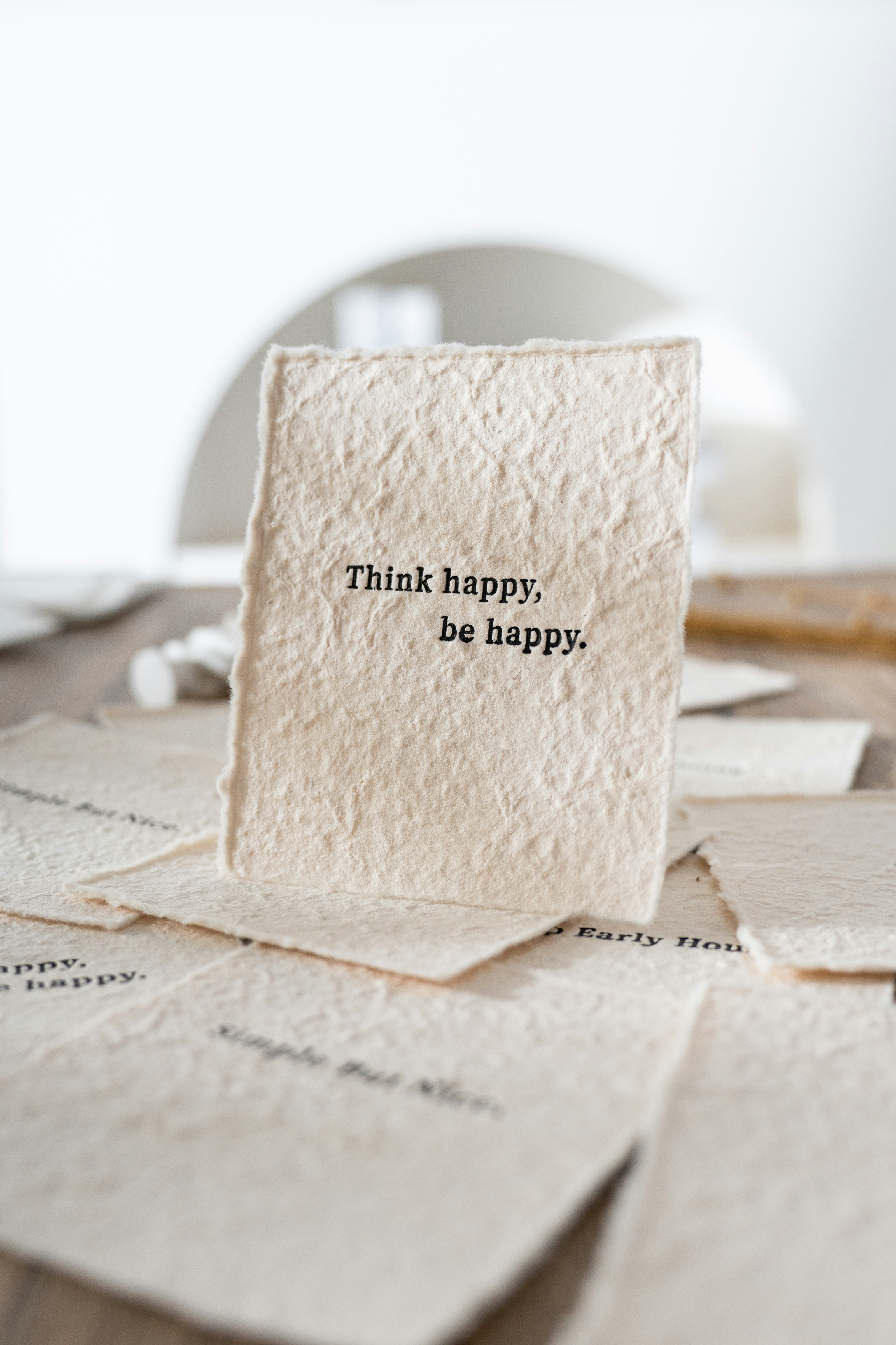 Texture-filled paper with a printed message stands upright among scattered torn sheets on a light-toned surface.