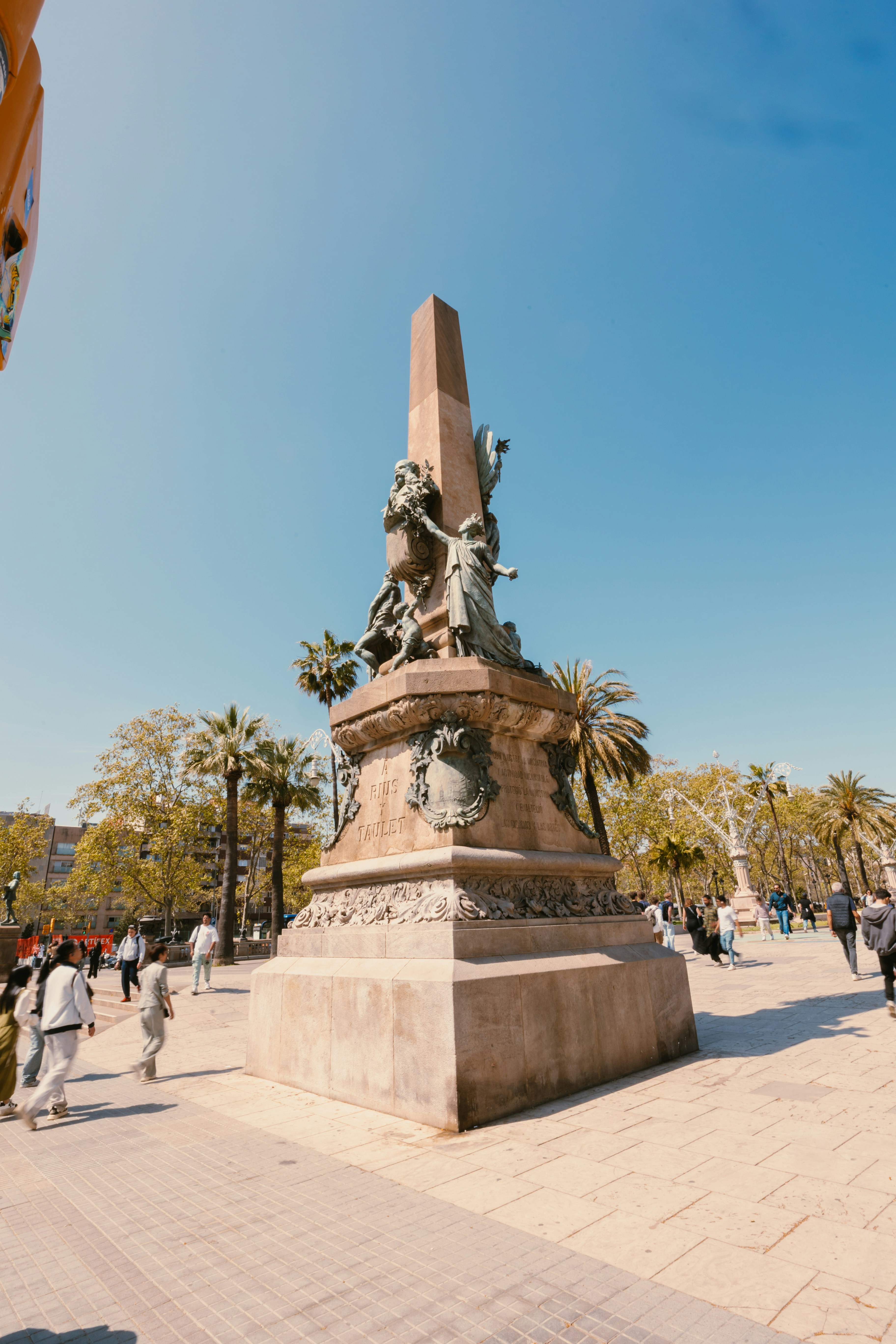 Monumental Shadow: A Statue Tower Rising Over a Palm-Lined Plaza